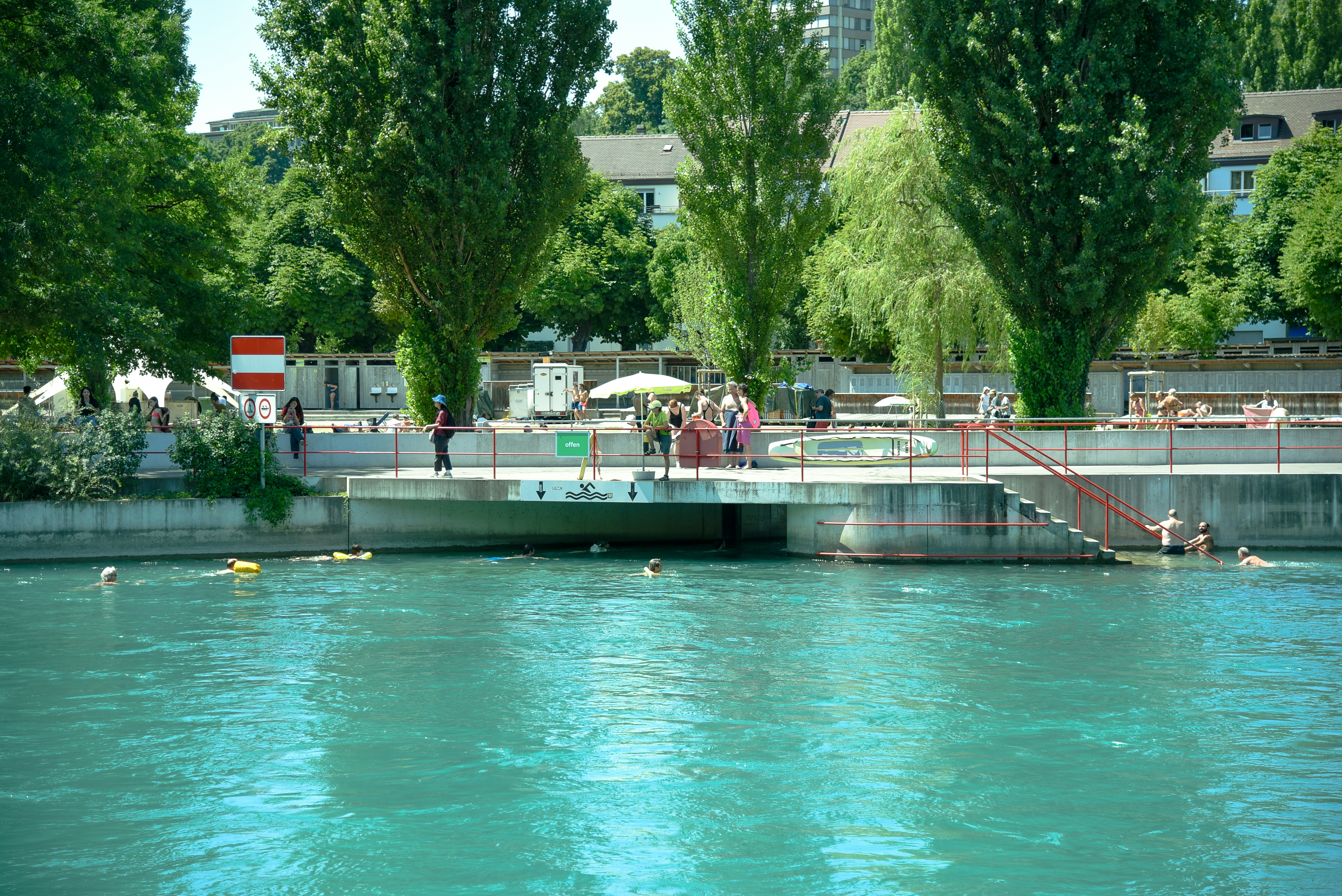 Turquoise Waters and Riverside Activity by a City Pool