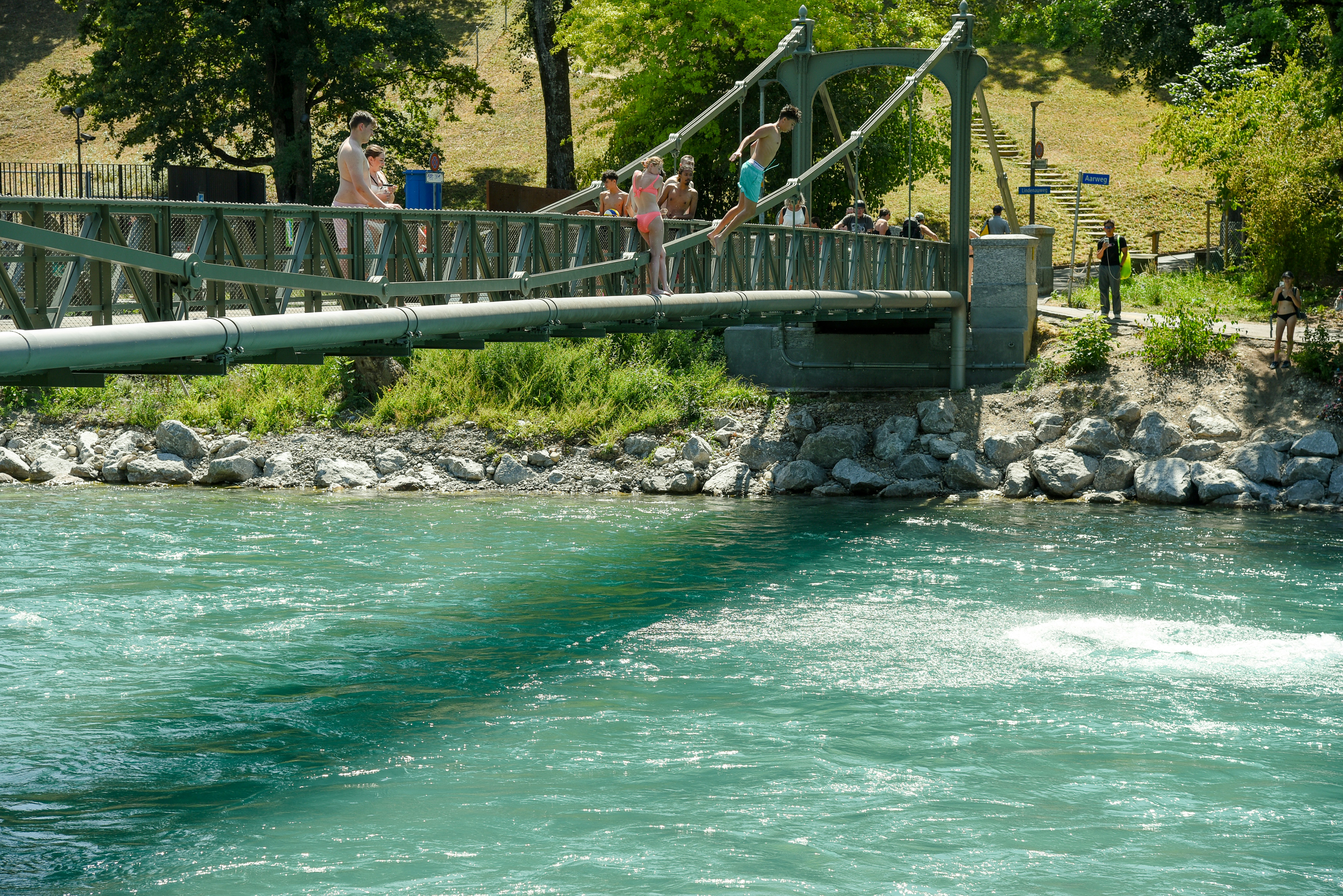 Pedestrian Bridge over Turquoise River: People Crossing a Scenic Channel