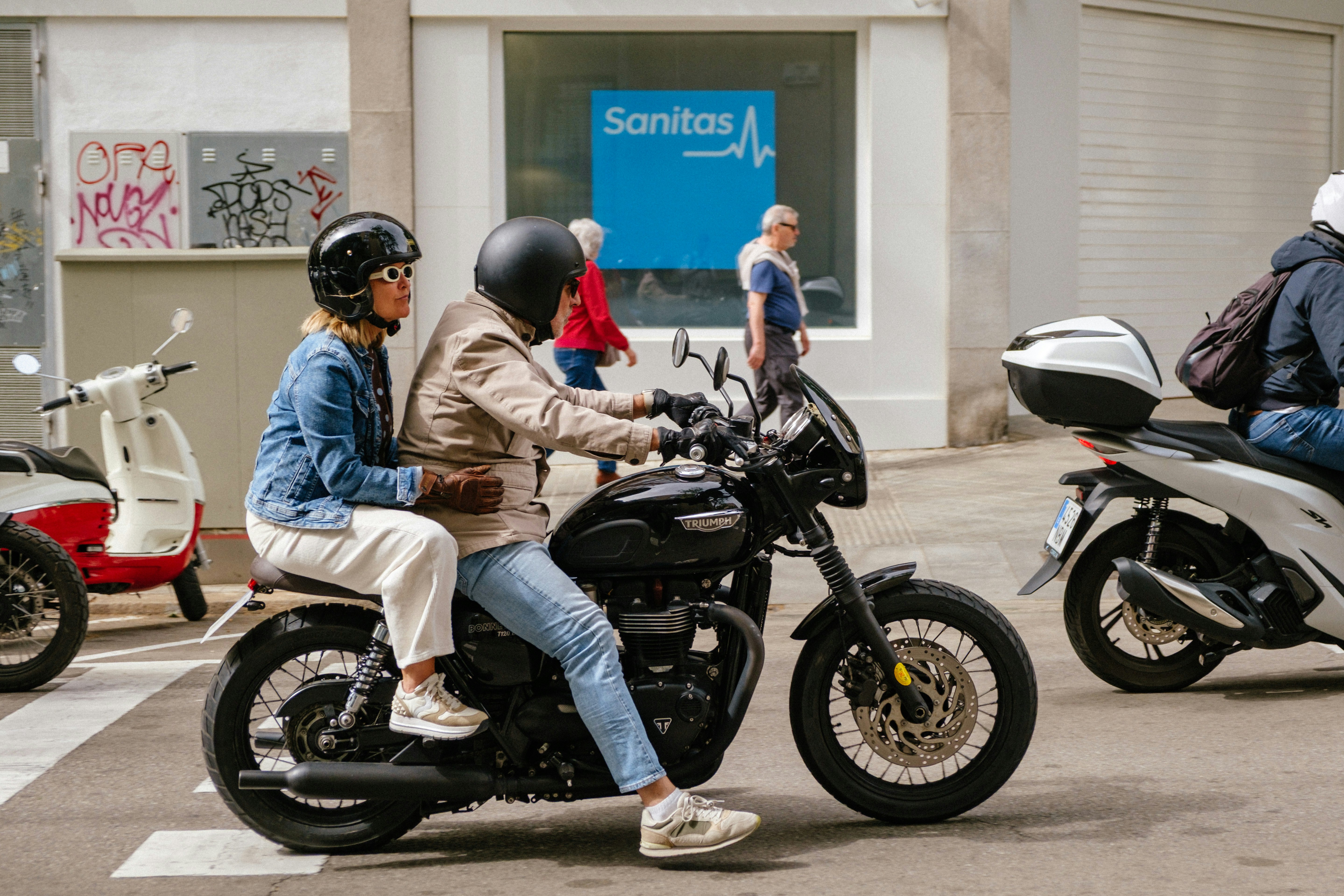 Rider Pair on a Black Motorcycle Surrounded by Urban Street Scene