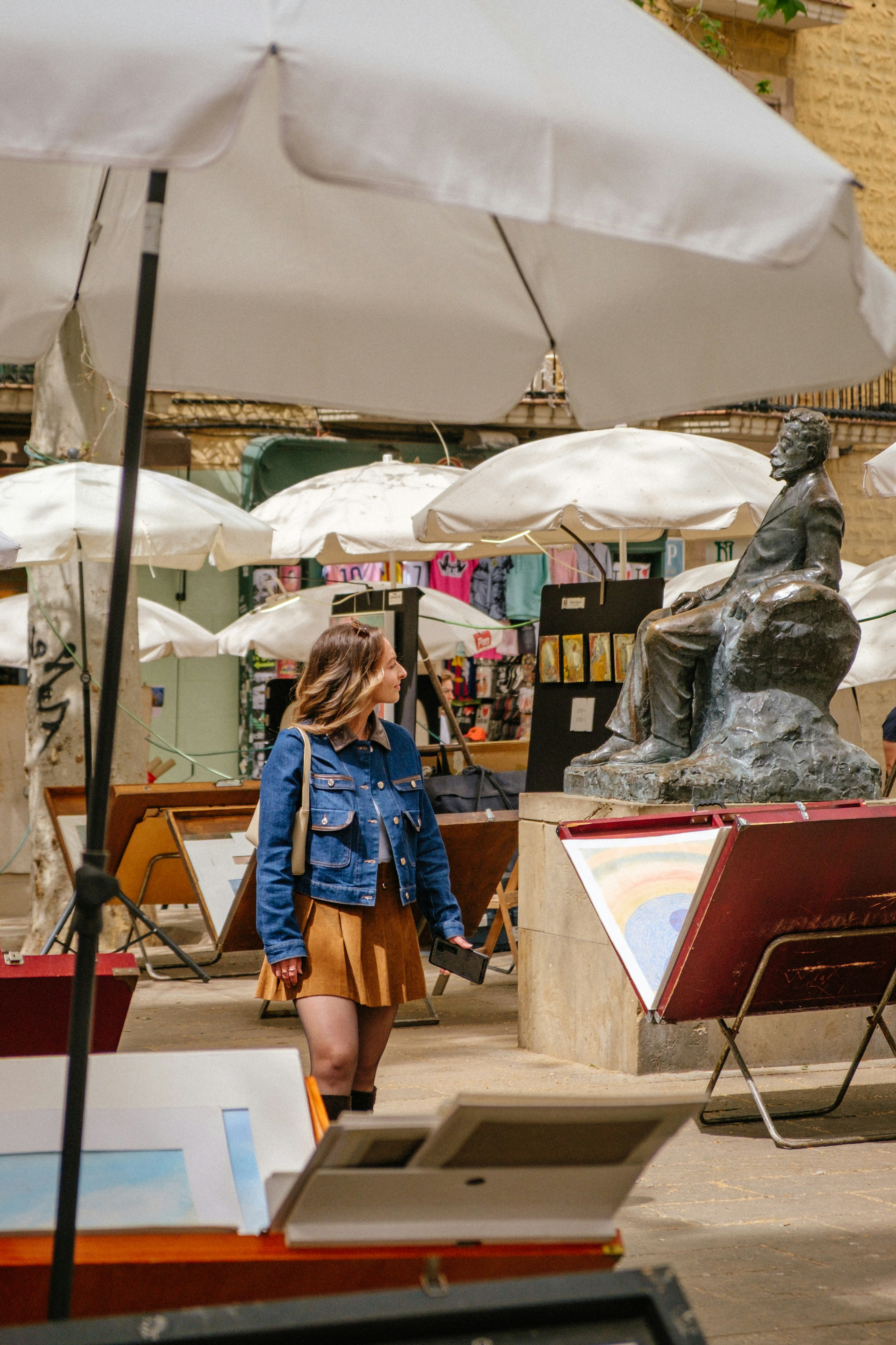 Street Portrait Amid Market Umbrellas and Bronze Statue