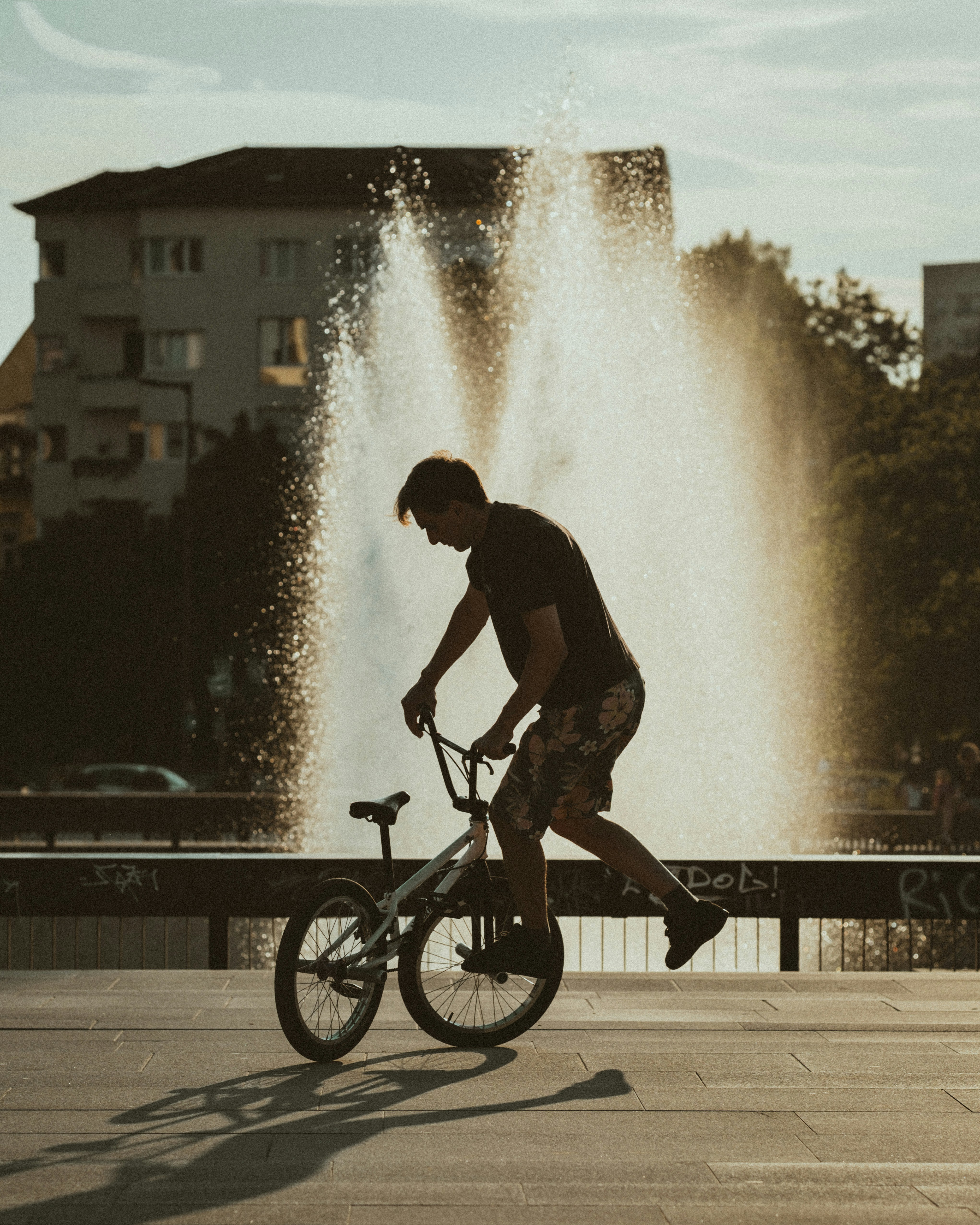Biker in the Jet of Light: A Quiet Moment by the Fountain