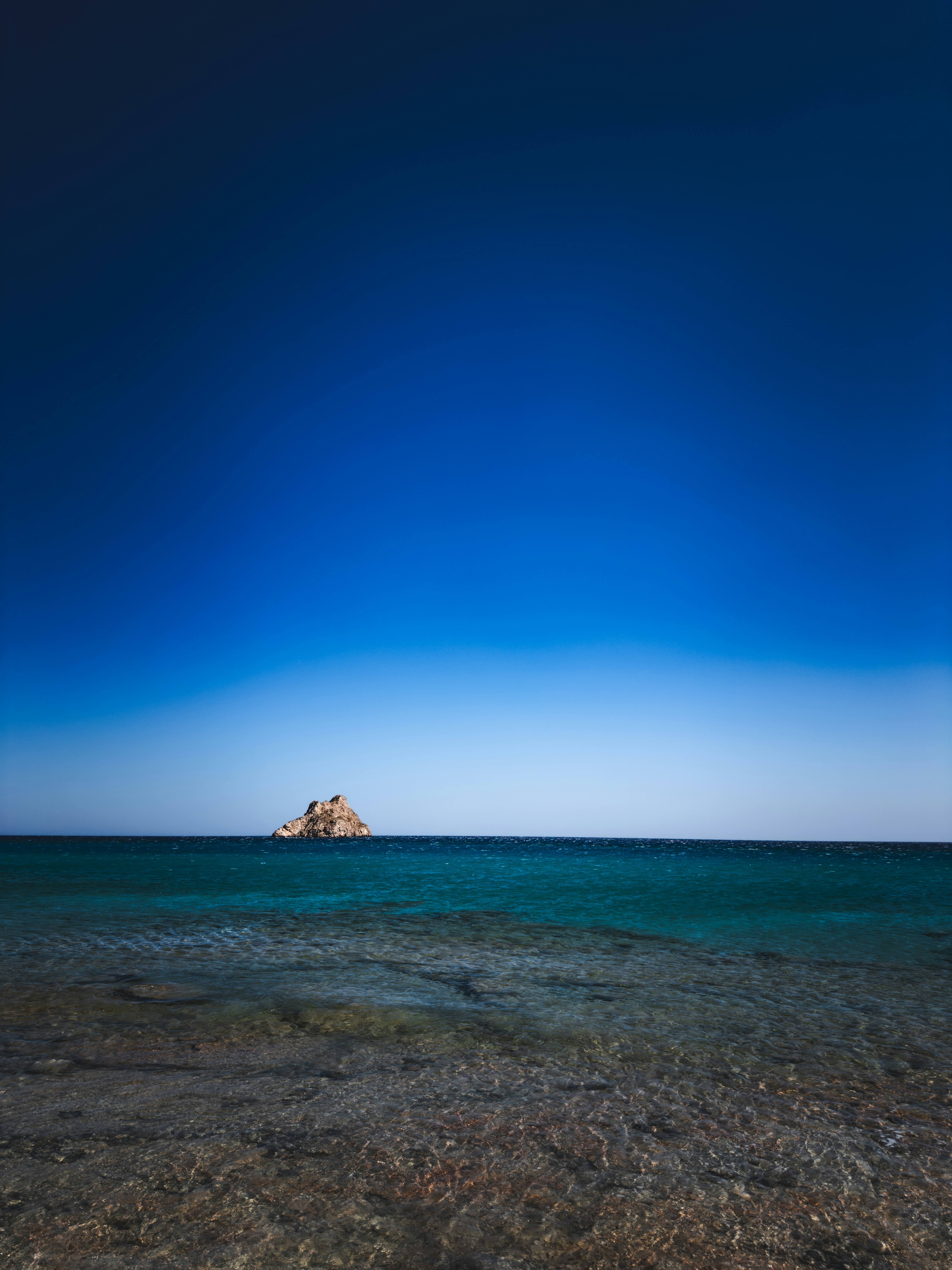  solitary rock in a calm sea under a gradient sky