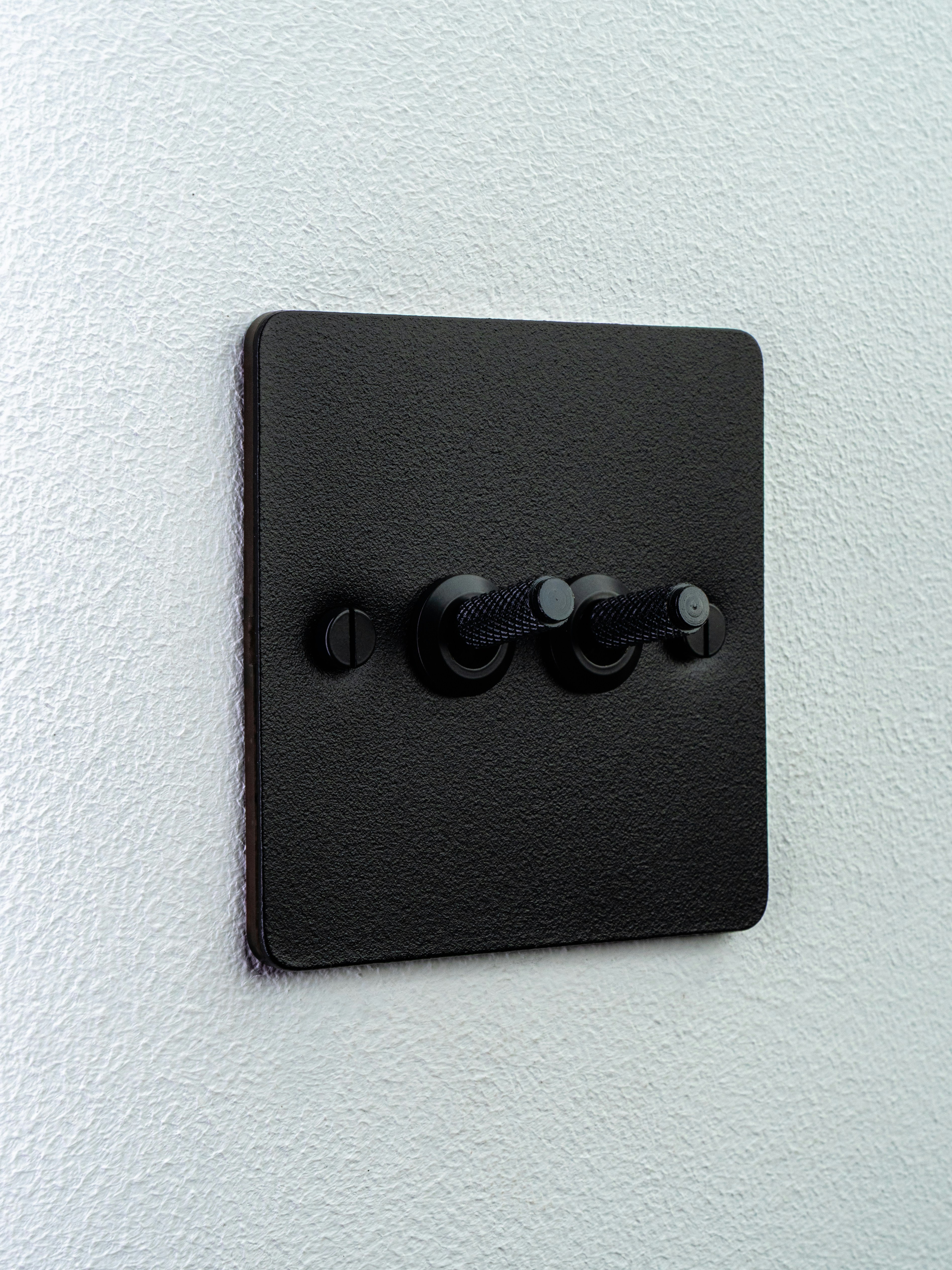 Close-up of a minimalist dimmer-style wall switch mounting on a textured wall