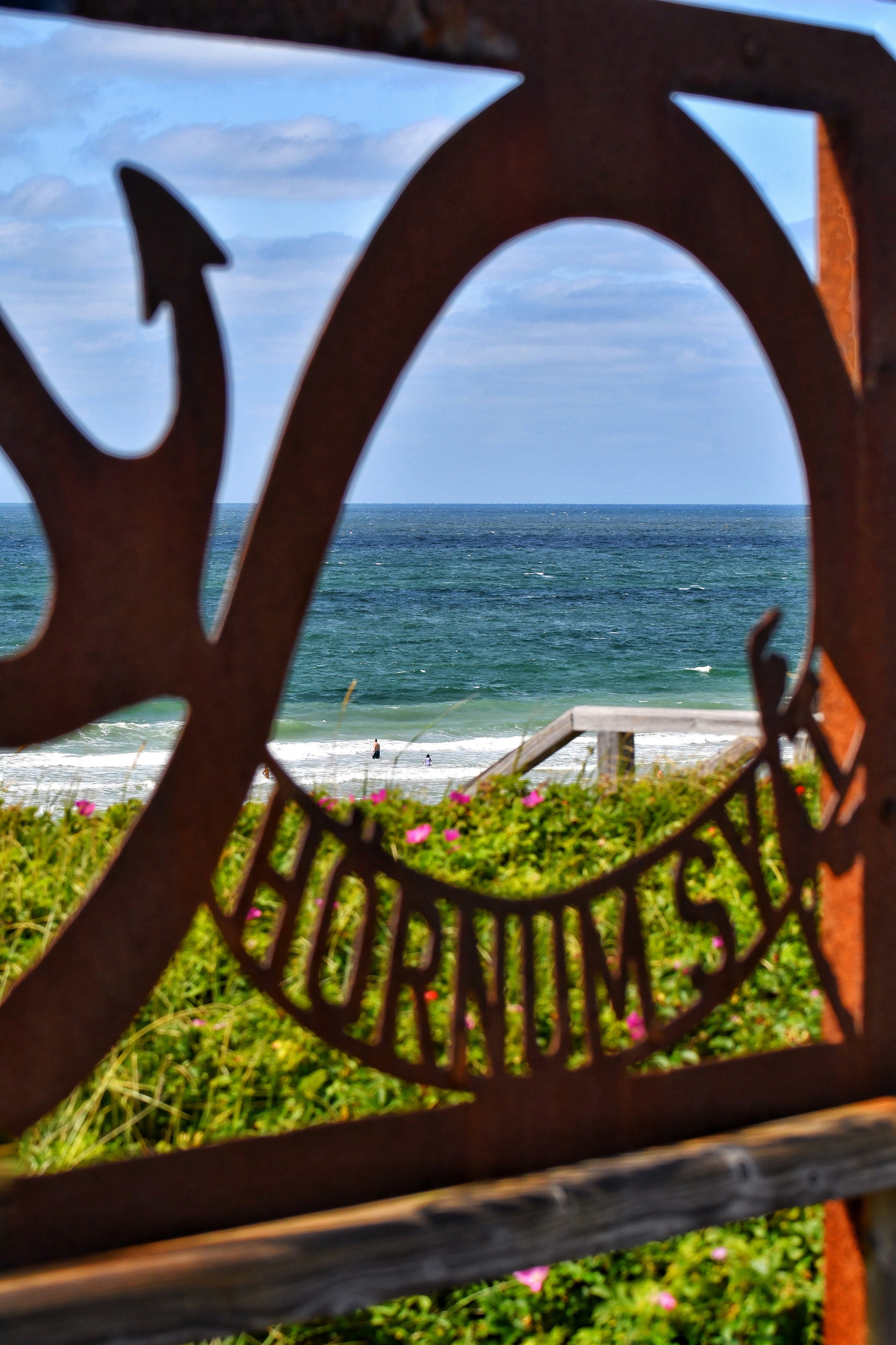 Iron Gate to the Sea: Framing a Coastal Vista Through Rustic Cutouts