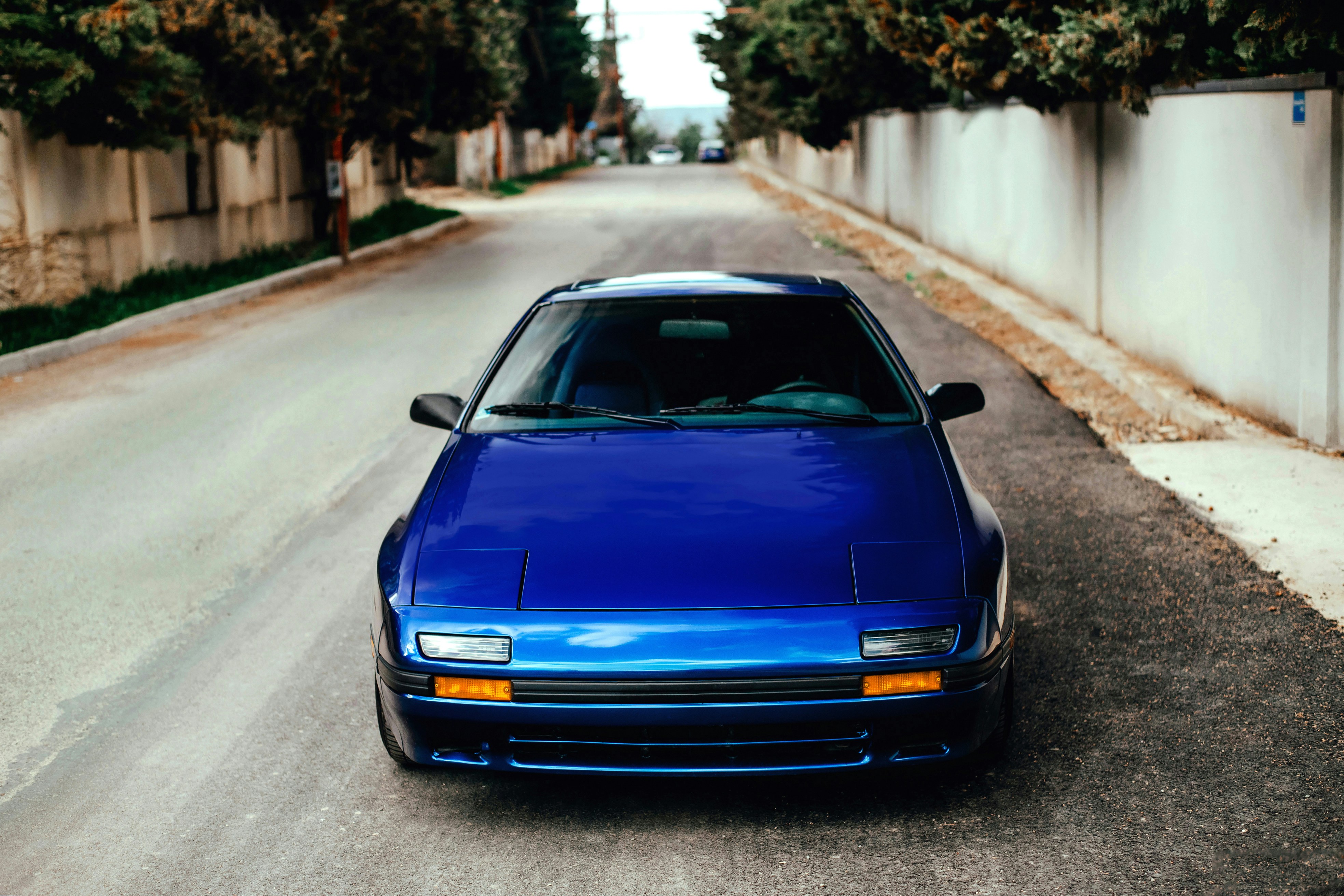 Blue coupe on a sunlit street, front-and-center