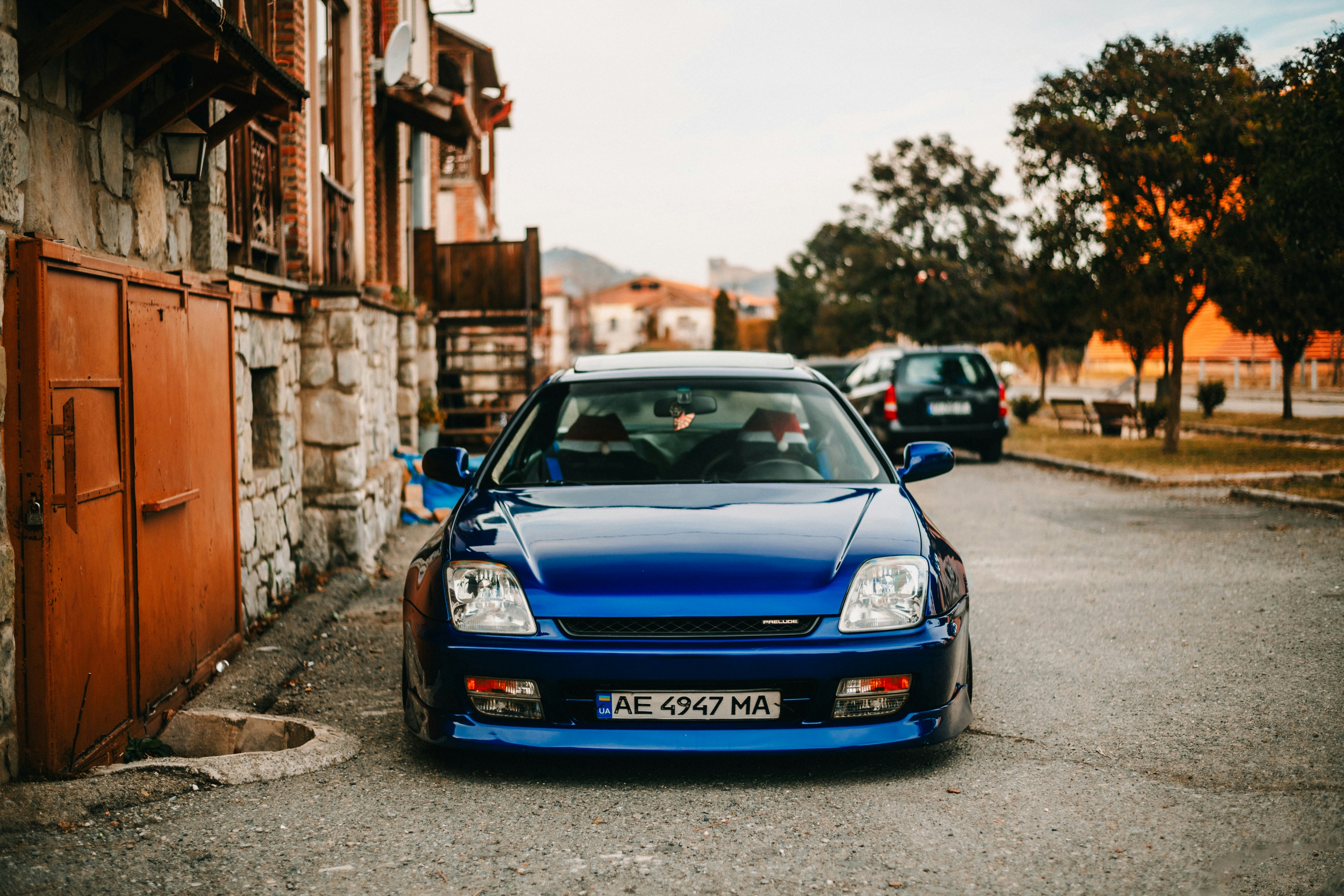Blue sedan at the end of a quiet street lined with rustic buildings