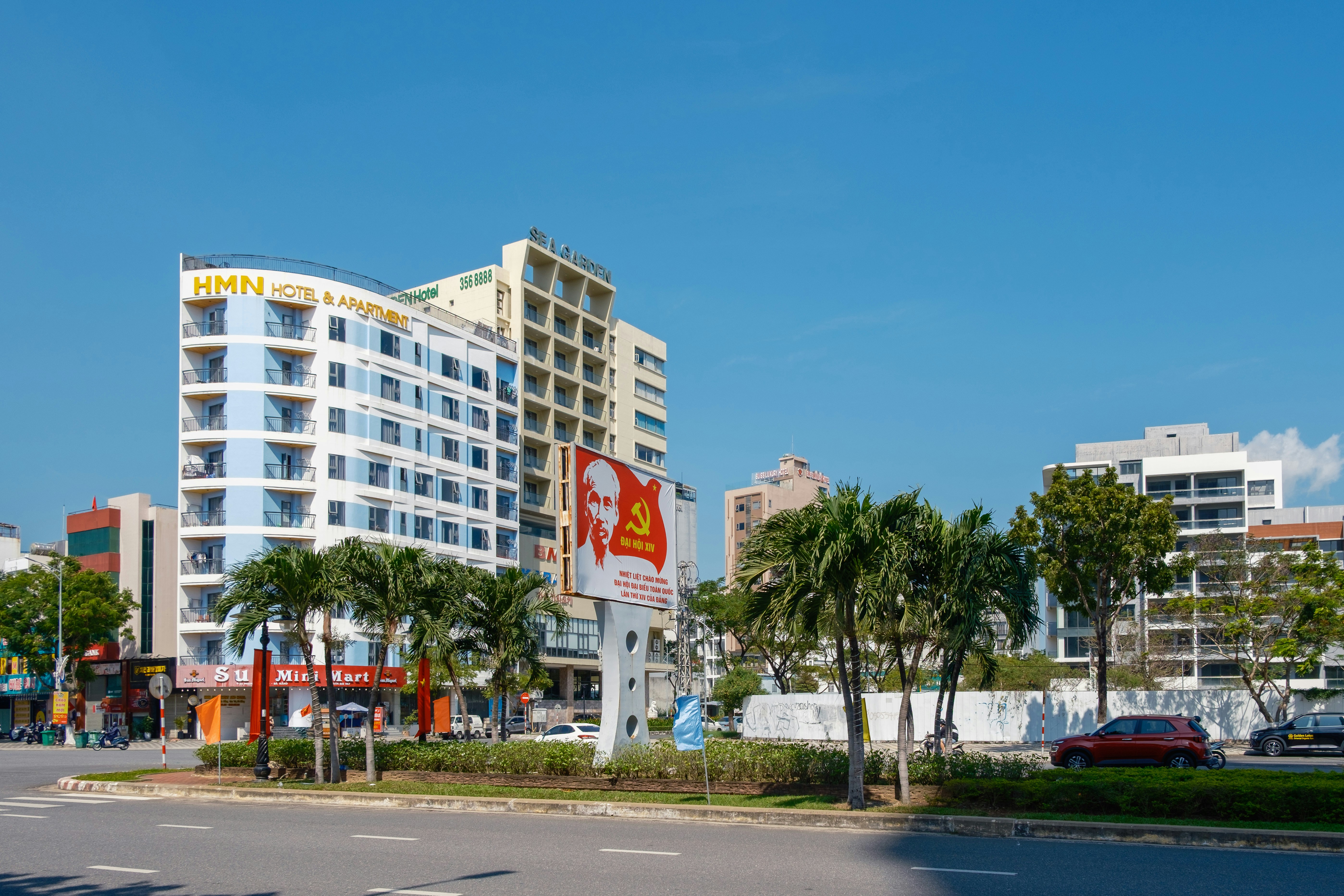Sunlit hotel row and palm-lined street under a clear blue sky