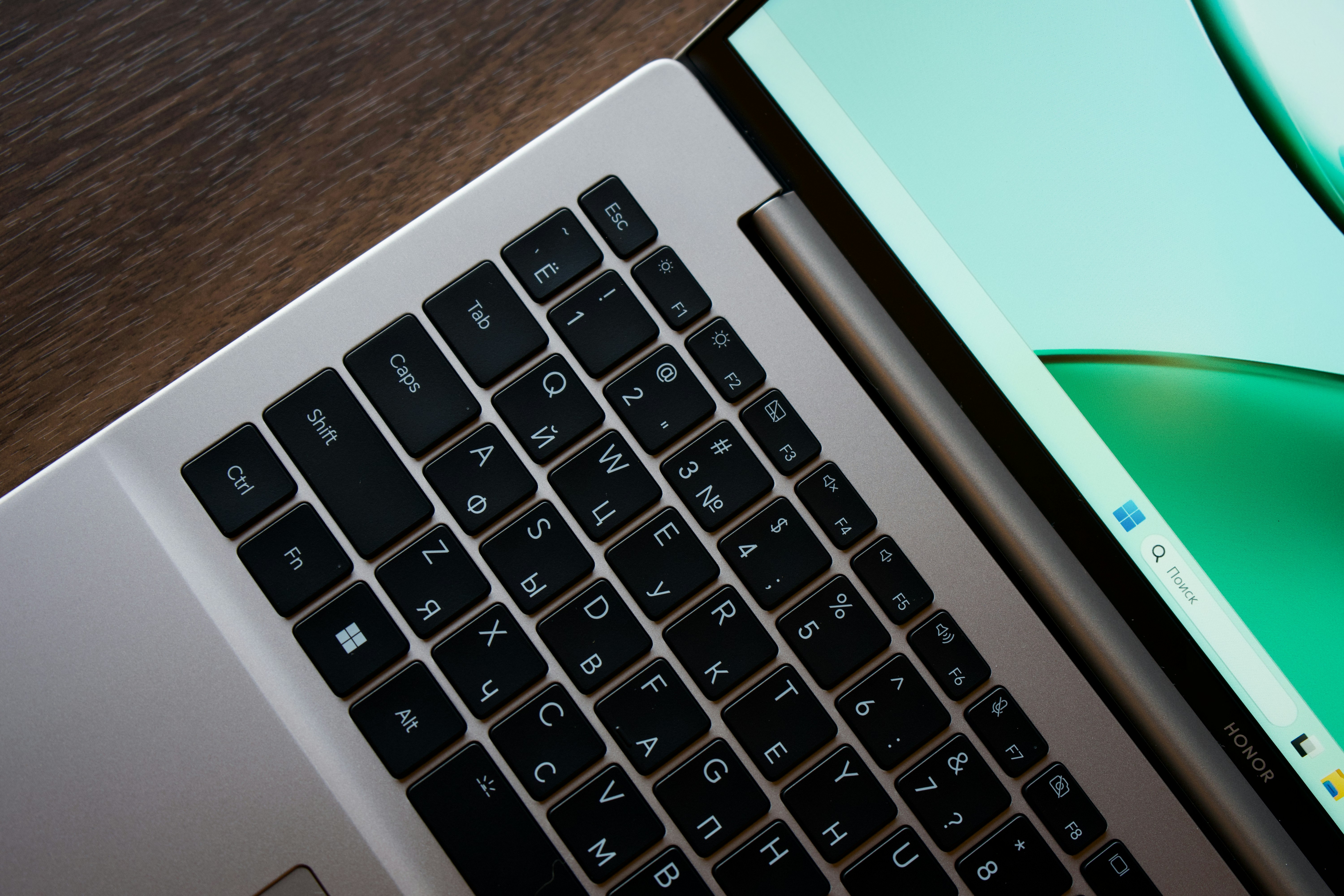 Neon glow on a silver keyboard: A laptop corner under soft green light