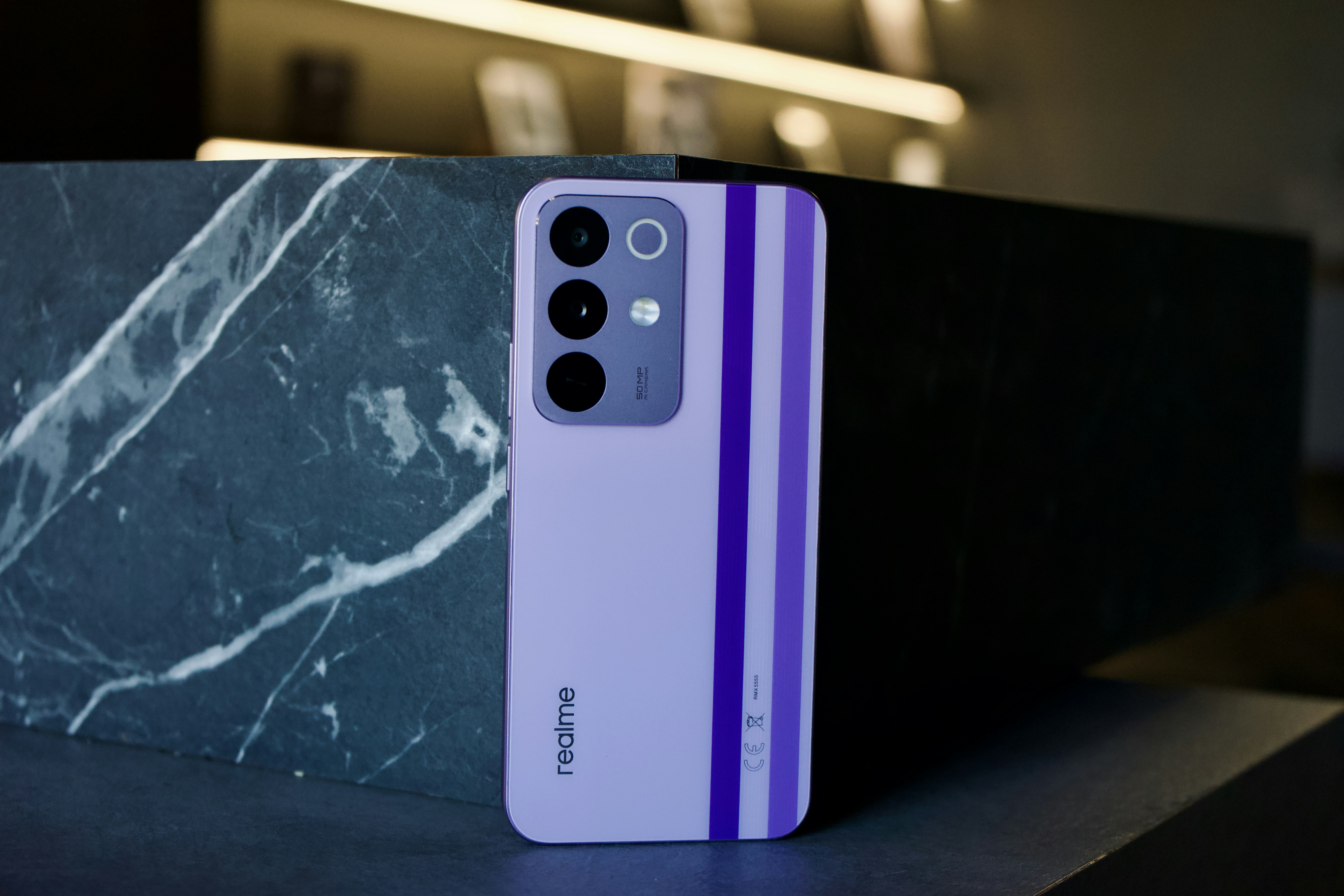 Purple Realme smartphone resting against a marble slab