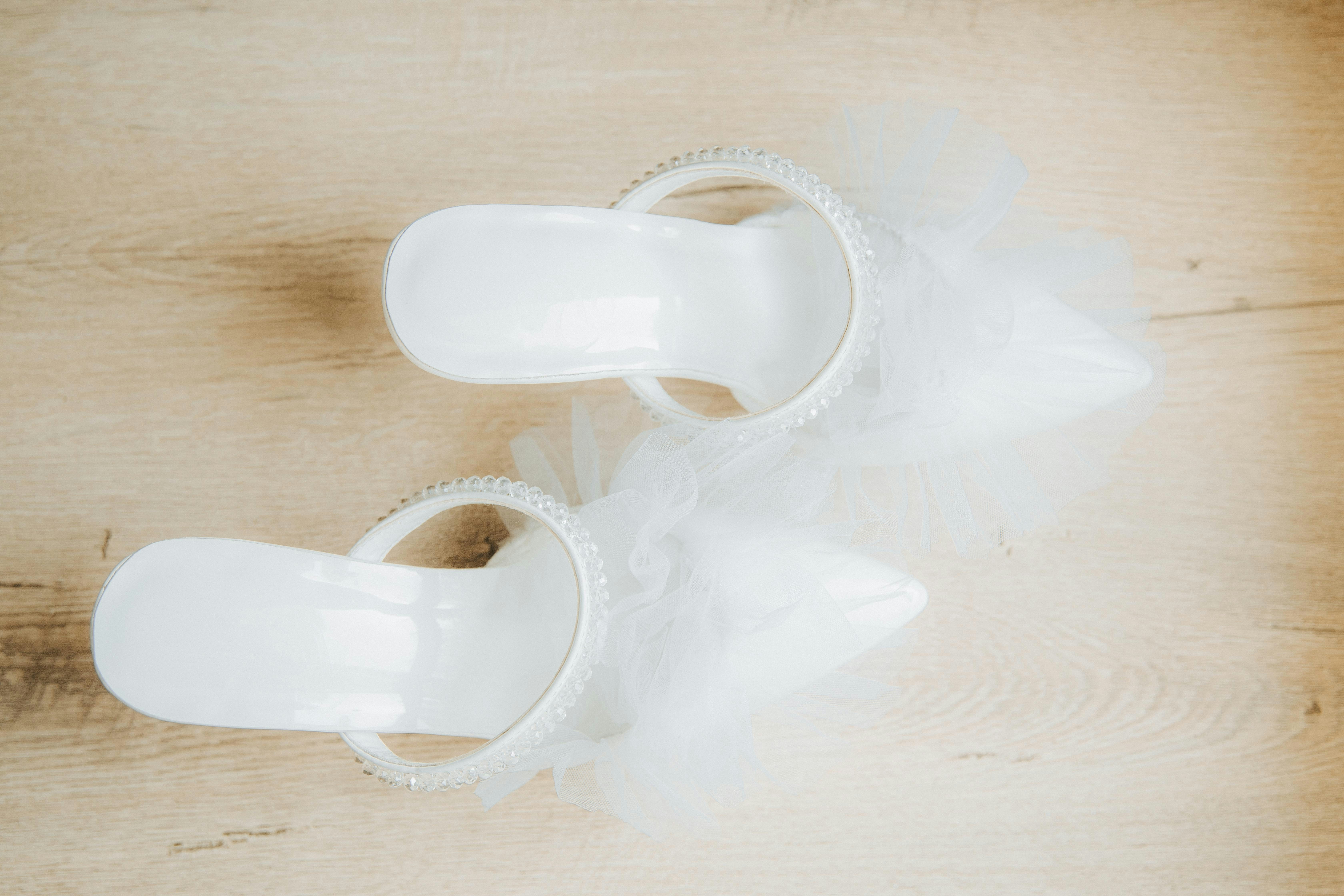 Tiny white ceremony: delicate baby shoes resting on pale wood