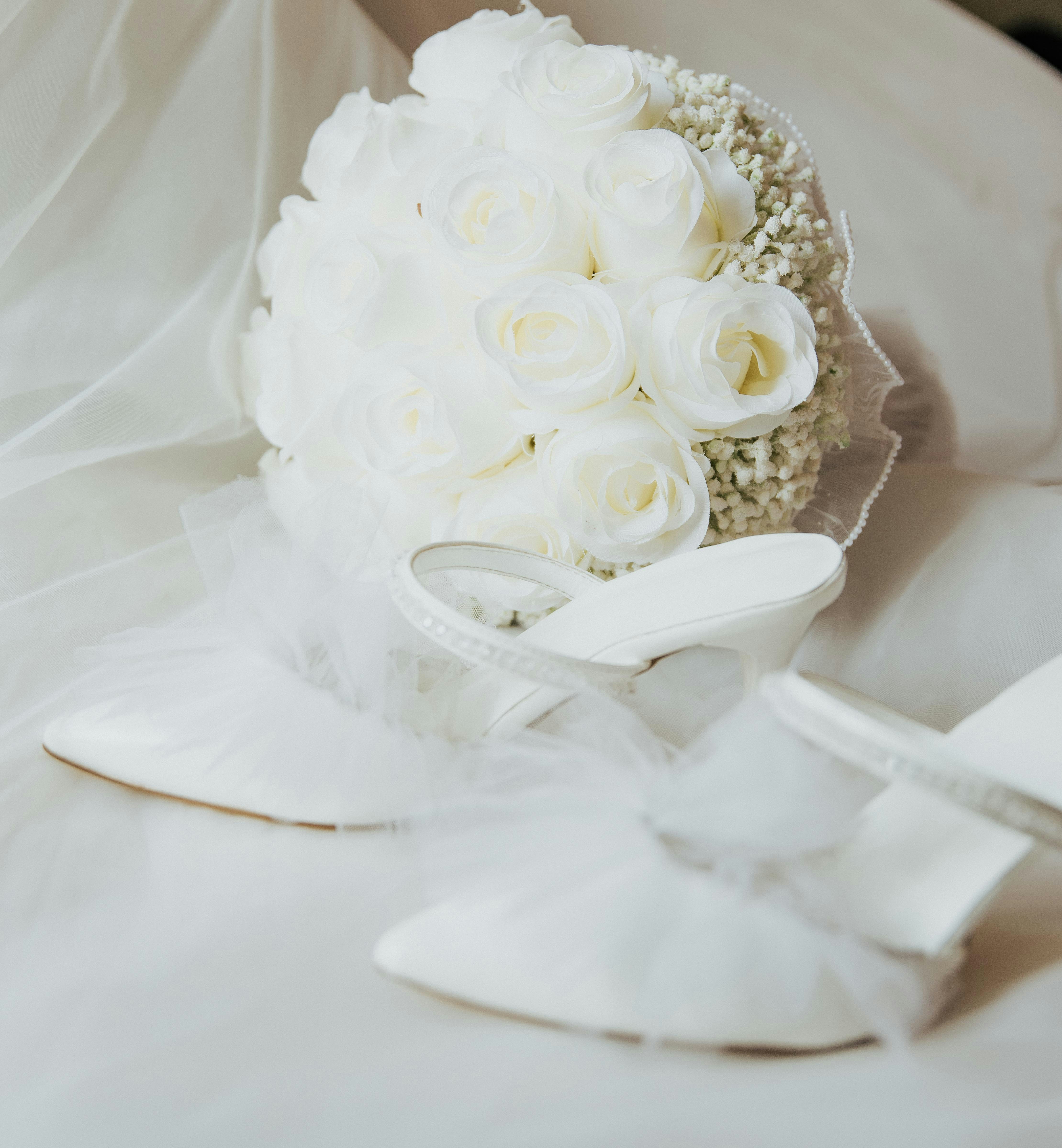 White bouquet in soft bridal veil with satin shoes