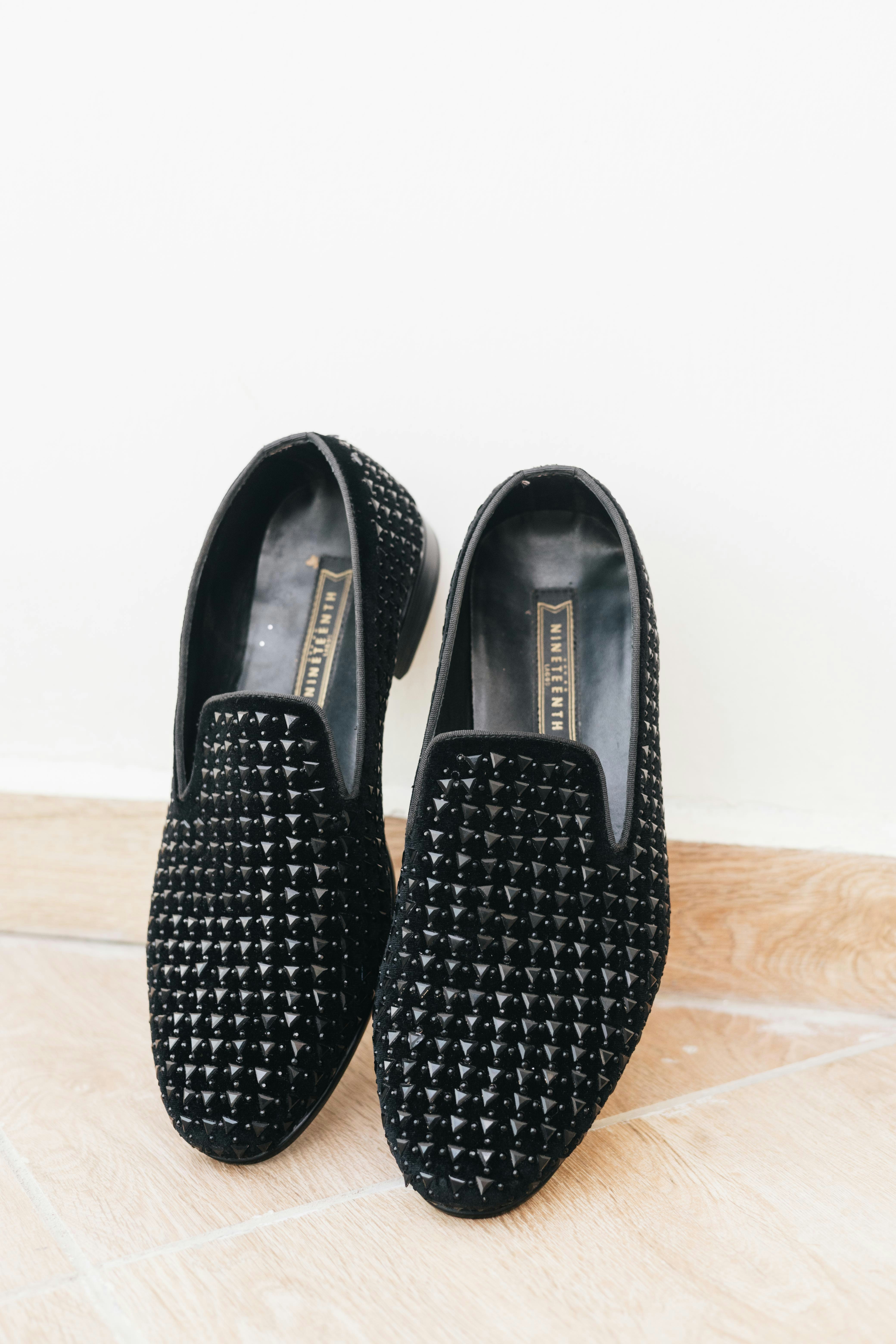 Black studded loafers resting on a warm tiled floor
