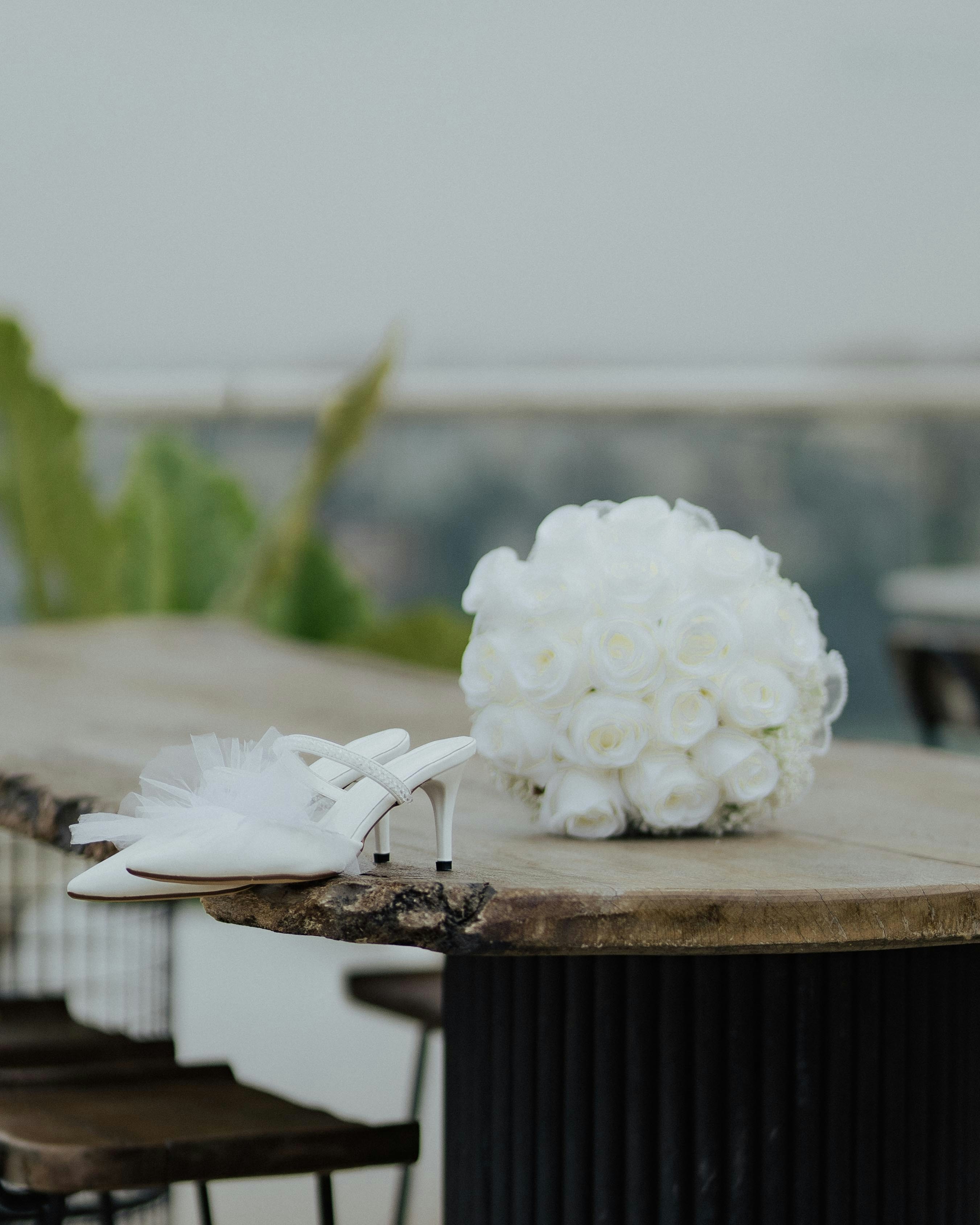 White Bouquet and Bridal Shoes Rest on a Weathered Table