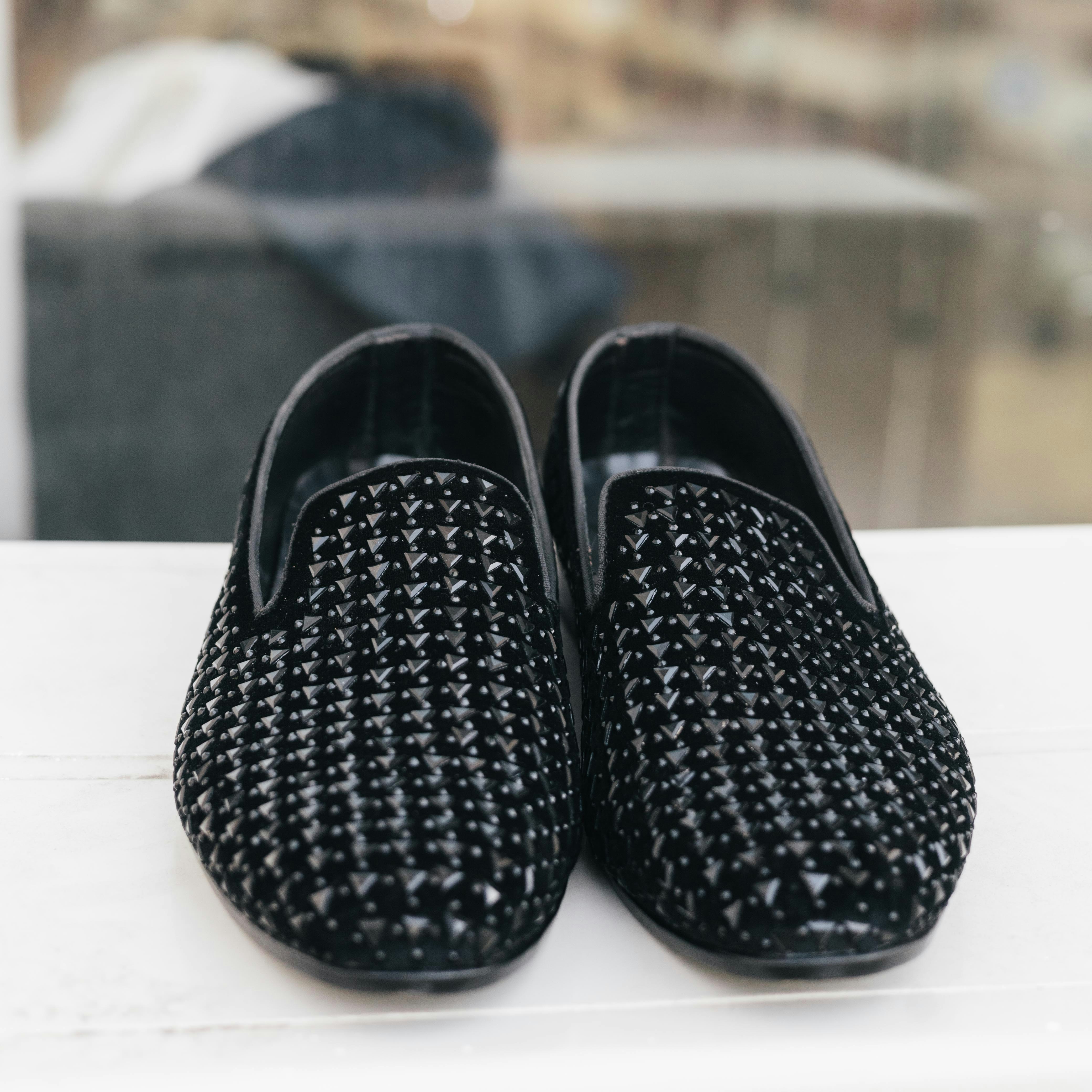 Black Embellished Slip-Ons Resting on a White Sill