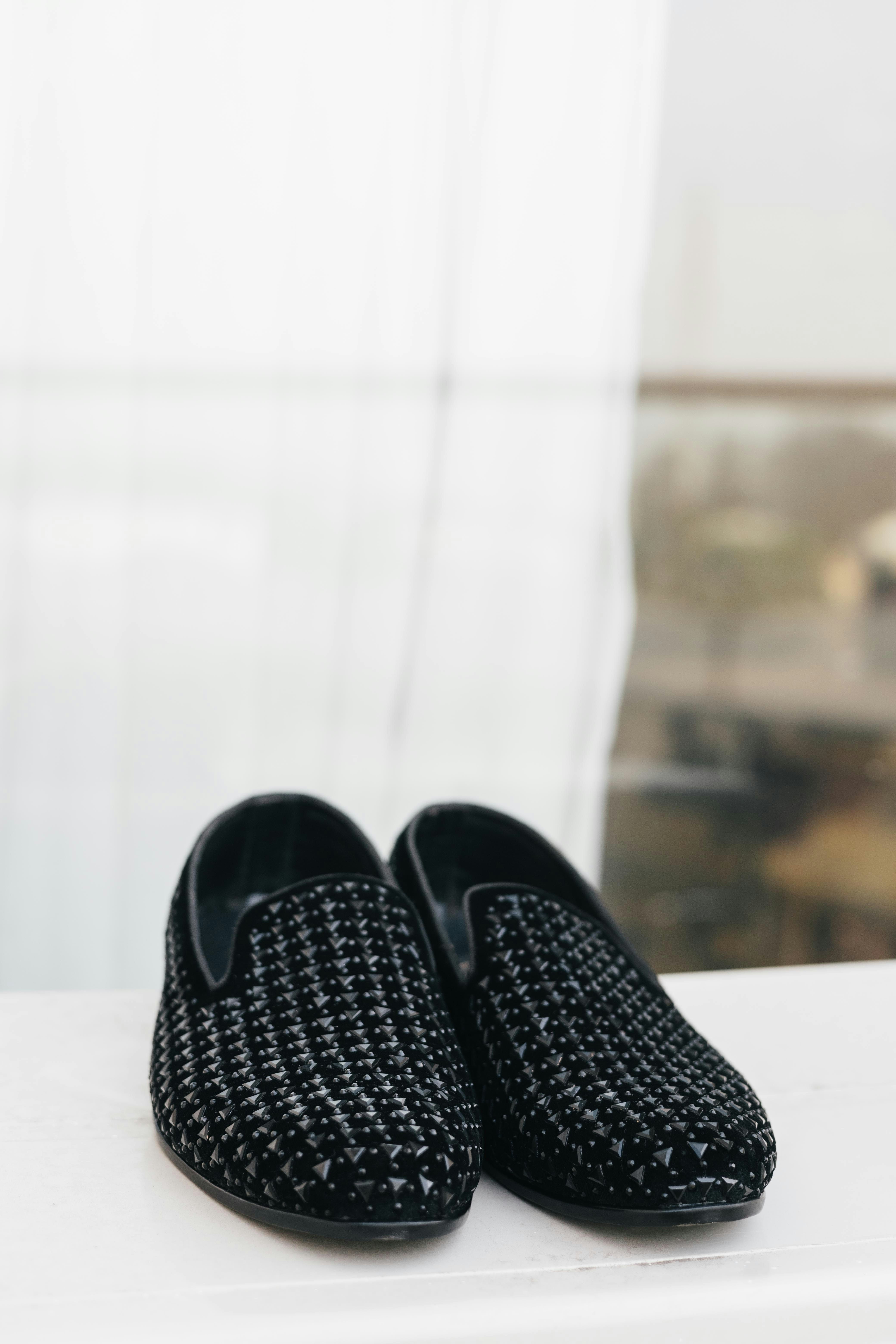 Shiny Studded Loafers Resting on a White Surface