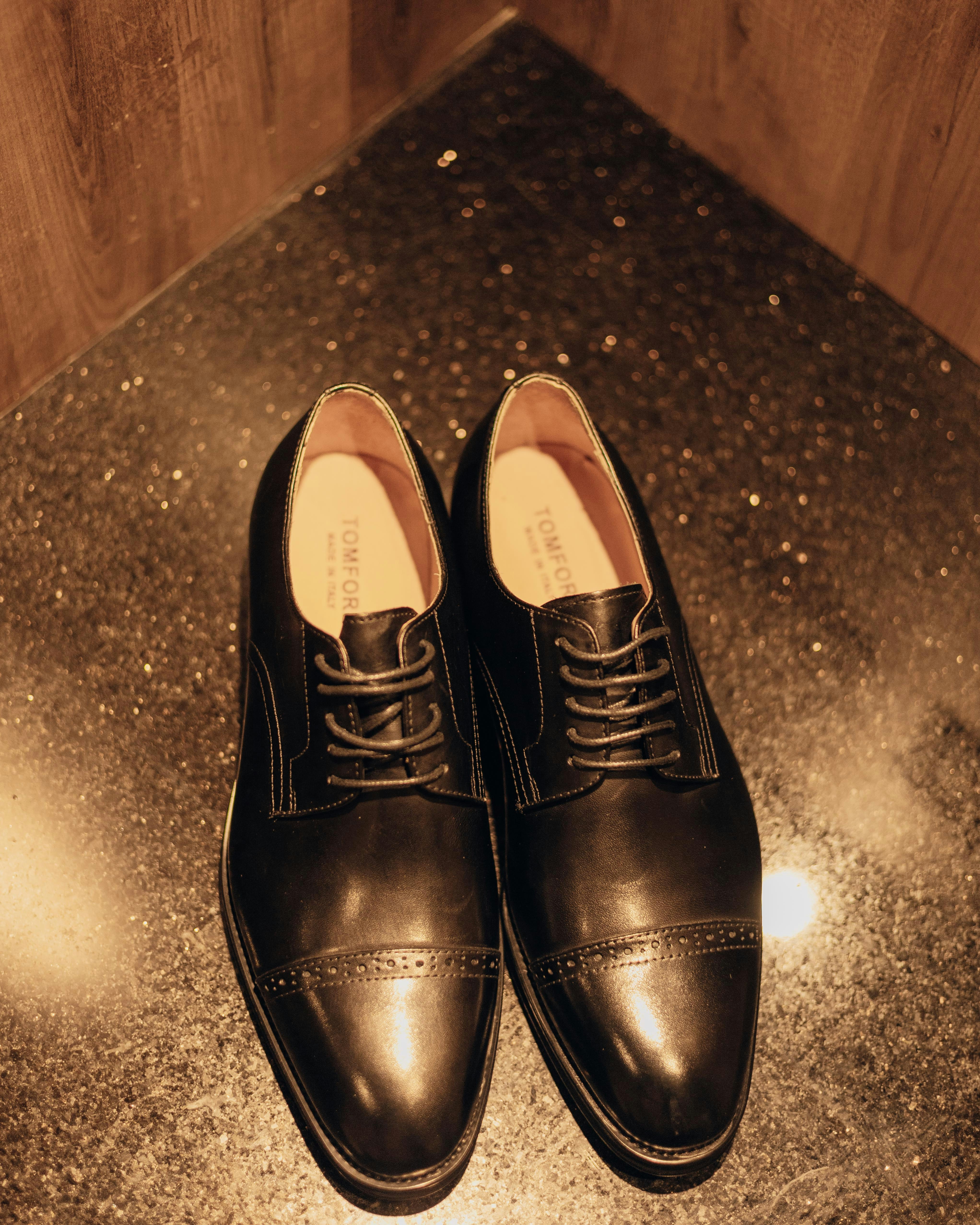Two polished dress shoes in a golden-lit hallway