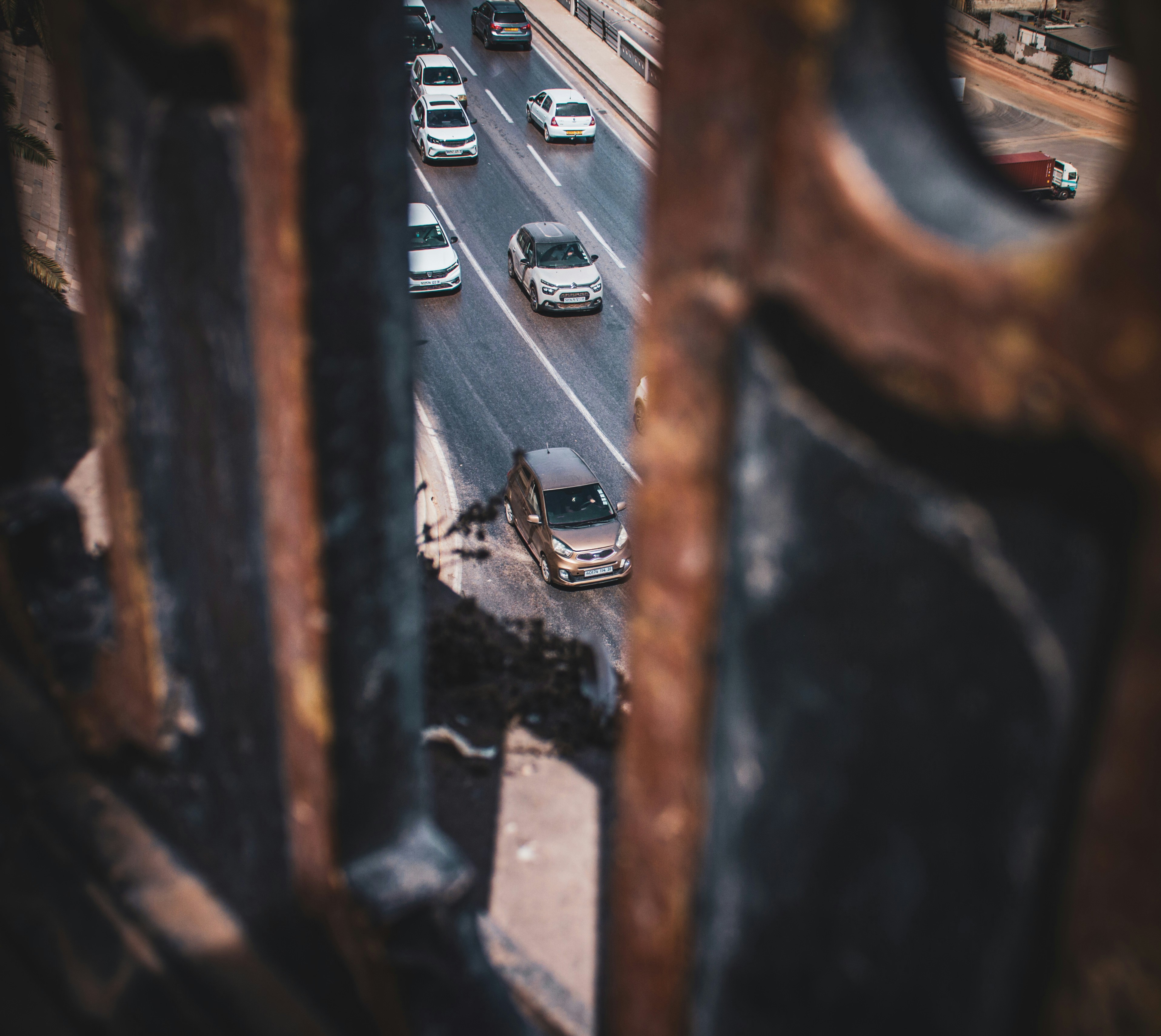 Through the Rails: Cars Framing a Narrow View Between Steel