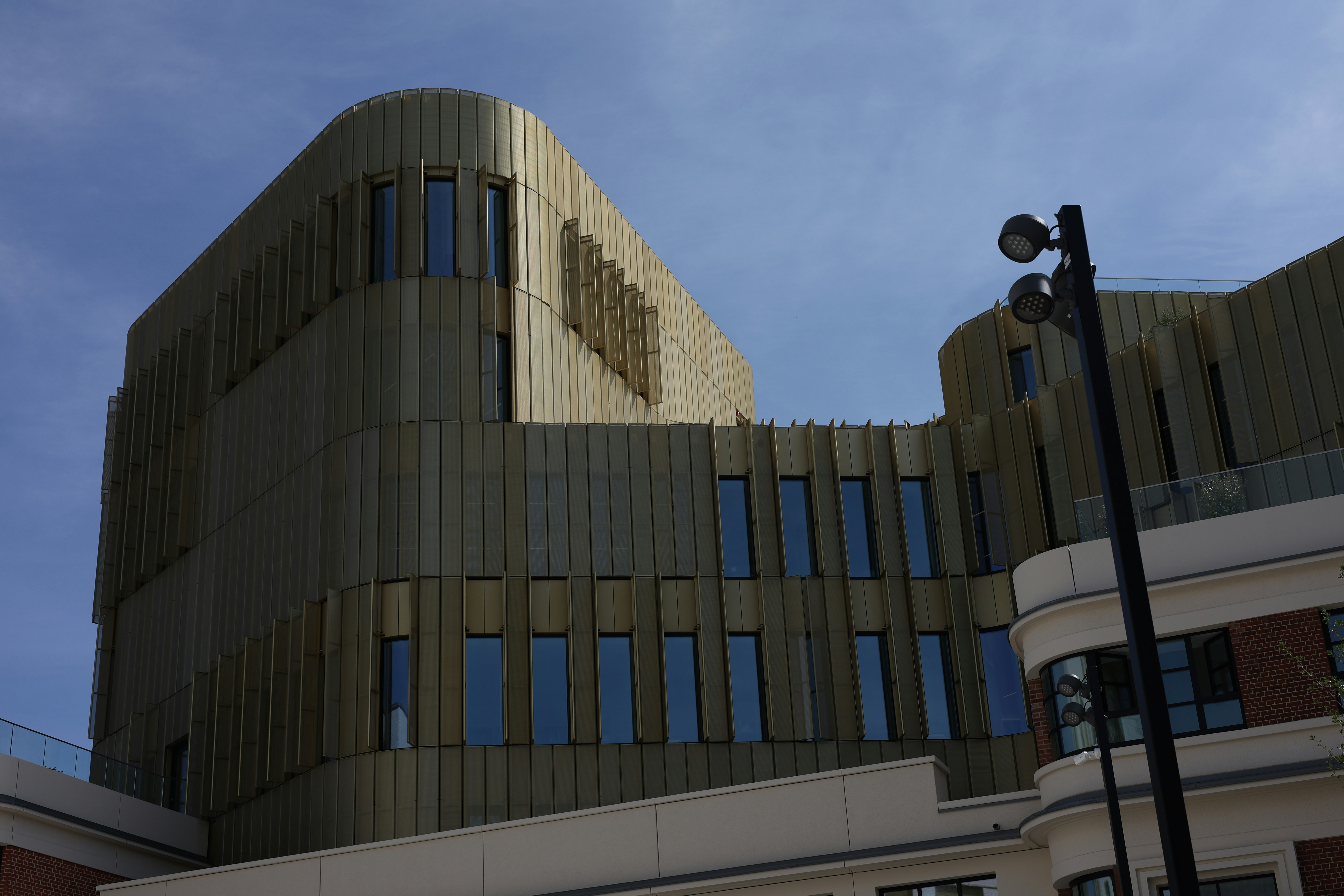 Modern building with vertical fins and blue windows bathed in warm afternoon light, capturing architectural detail and contrast.