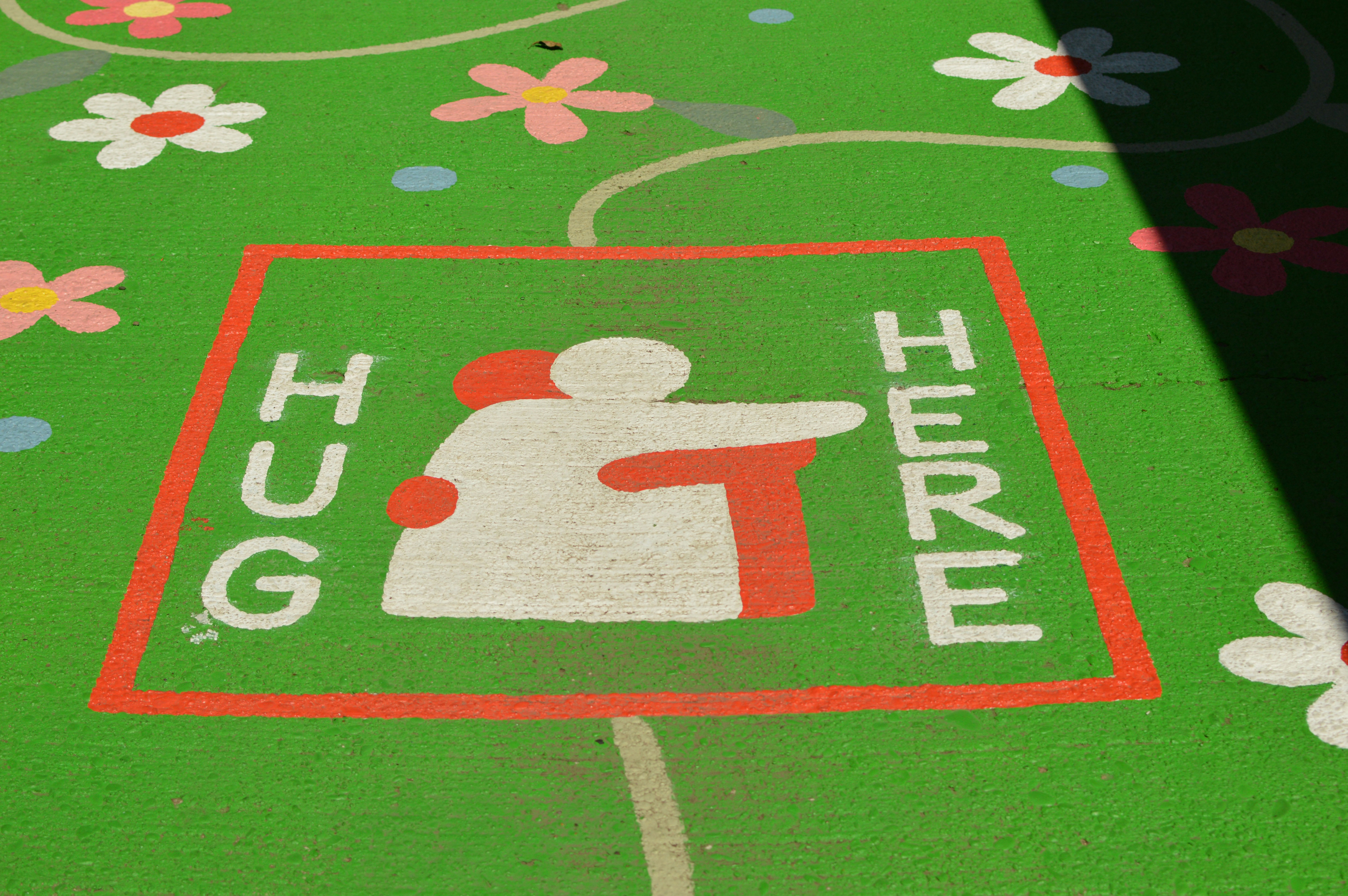Green pedestrian crosswalk emblem: hugging figure within a red frame