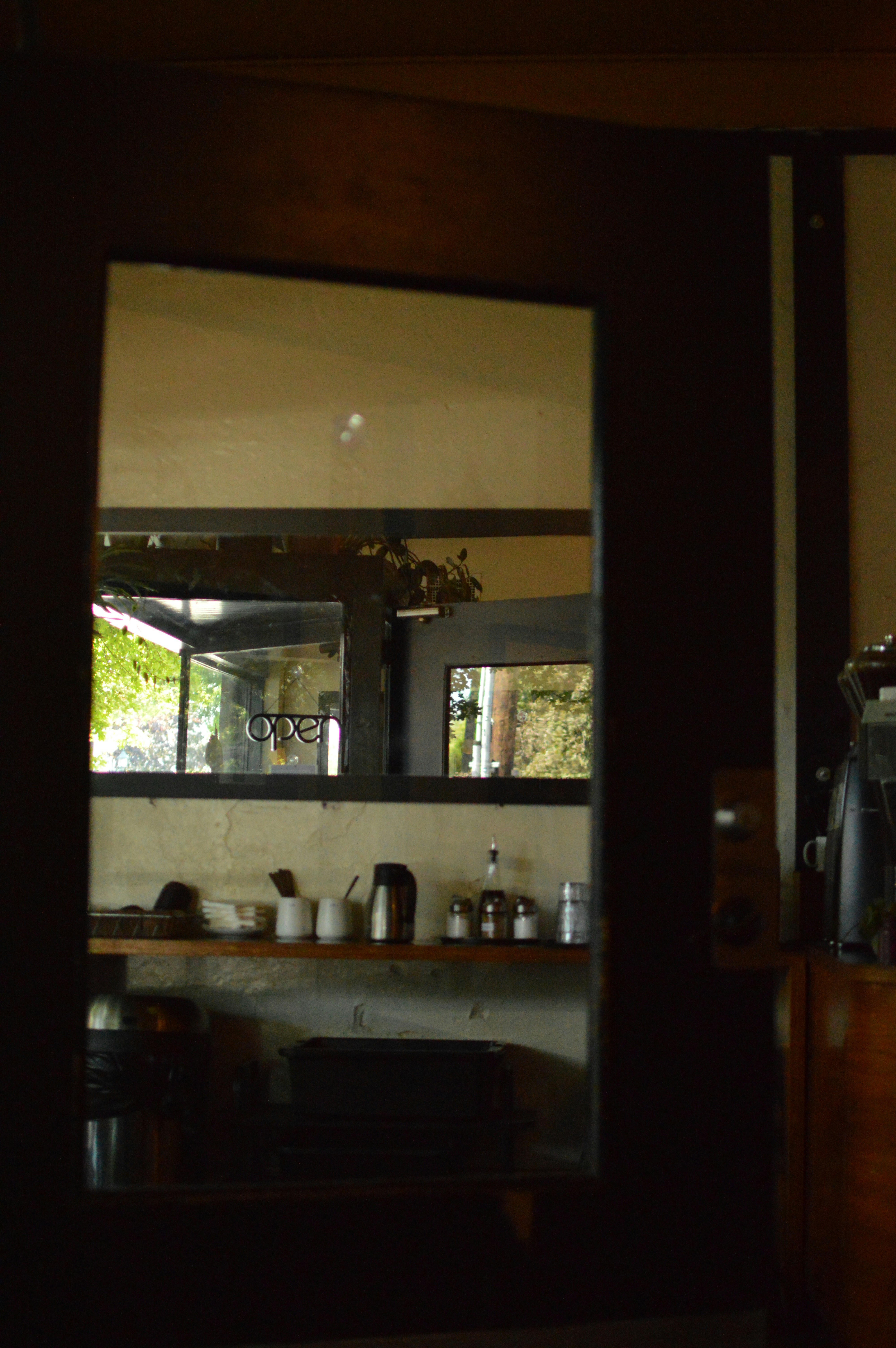 Through the Door: A Quiet Barista Corner Reflected in Glass