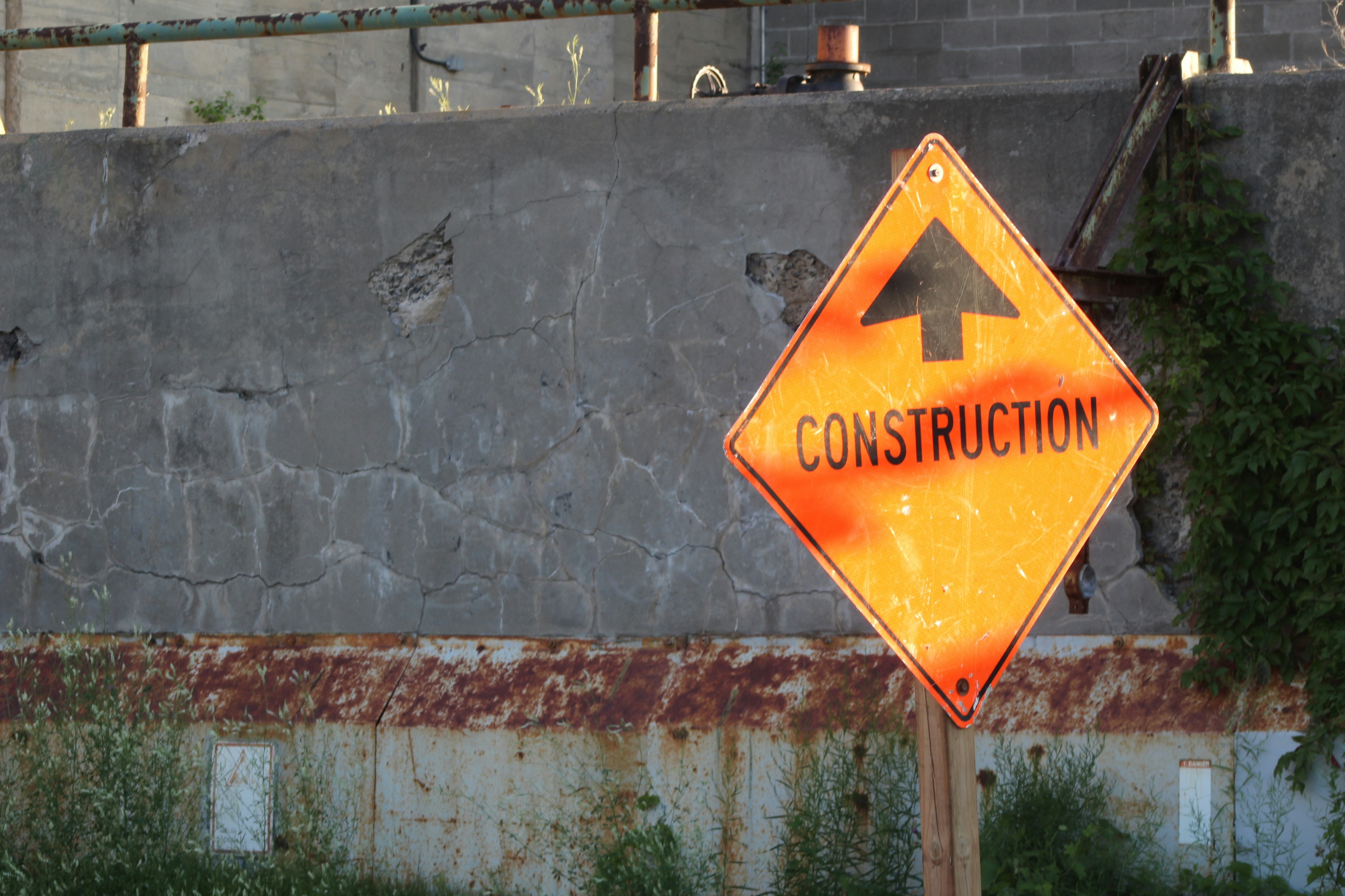 Orange Construction Sign Anchors a Weathered Wall