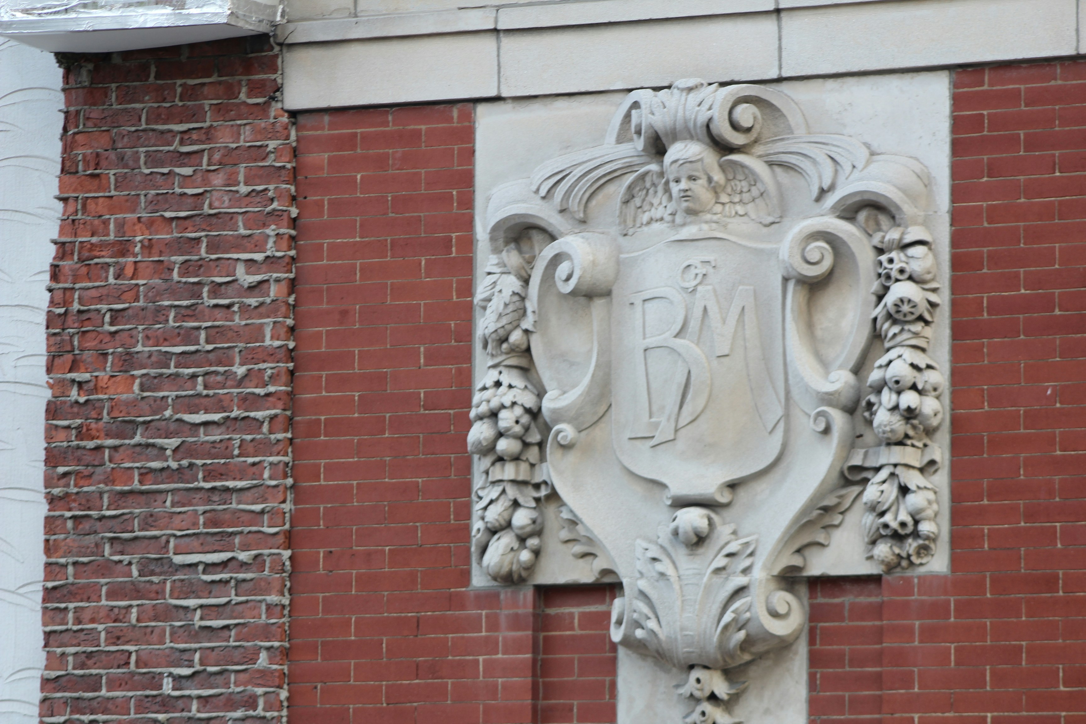 Carved Crest atop a Brick Wall: A Stone Emblem with Scrollwork and Grapes