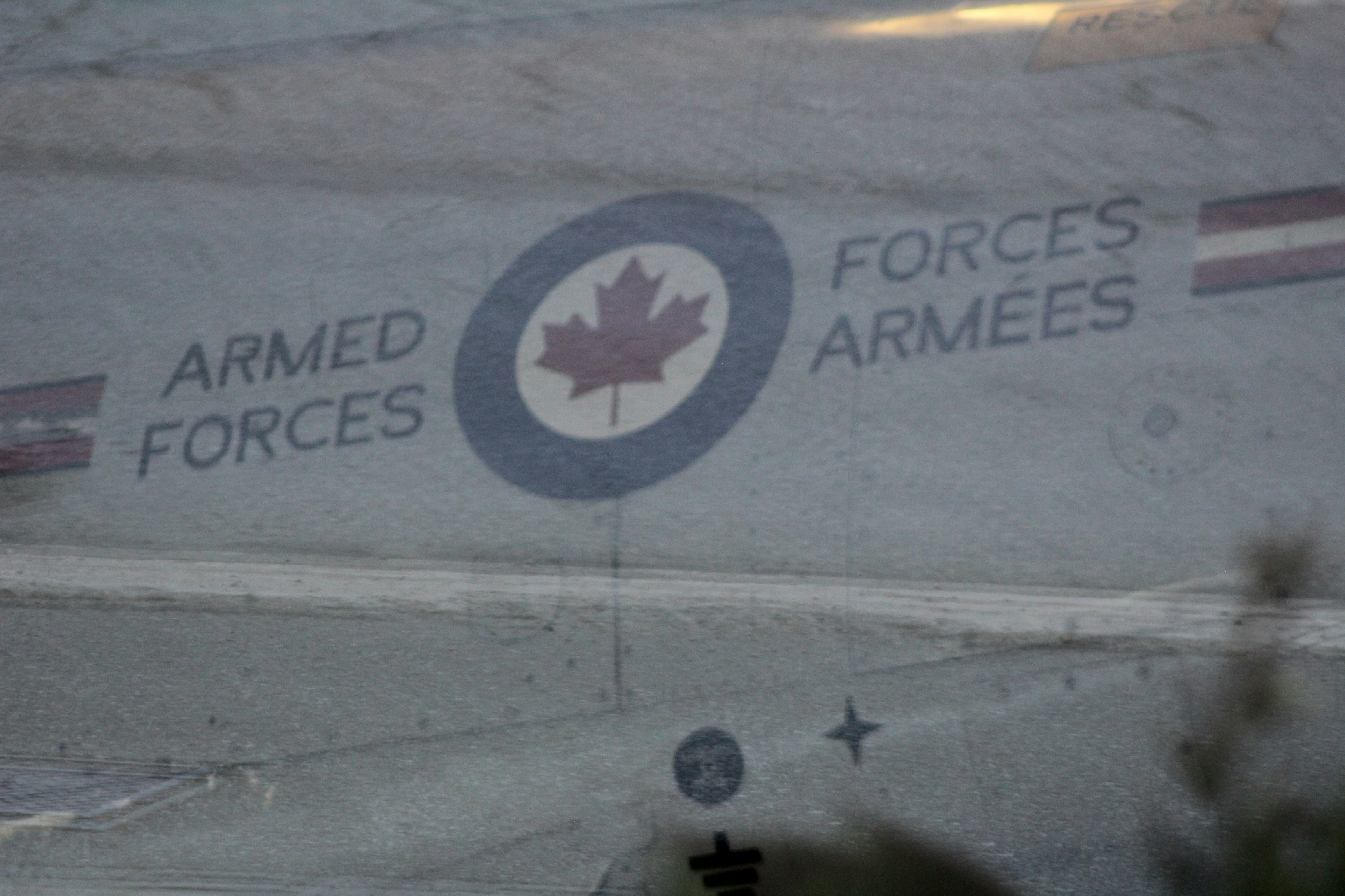 Emblem on a weathered tarmac: Canadian Forces insignia and maple crest