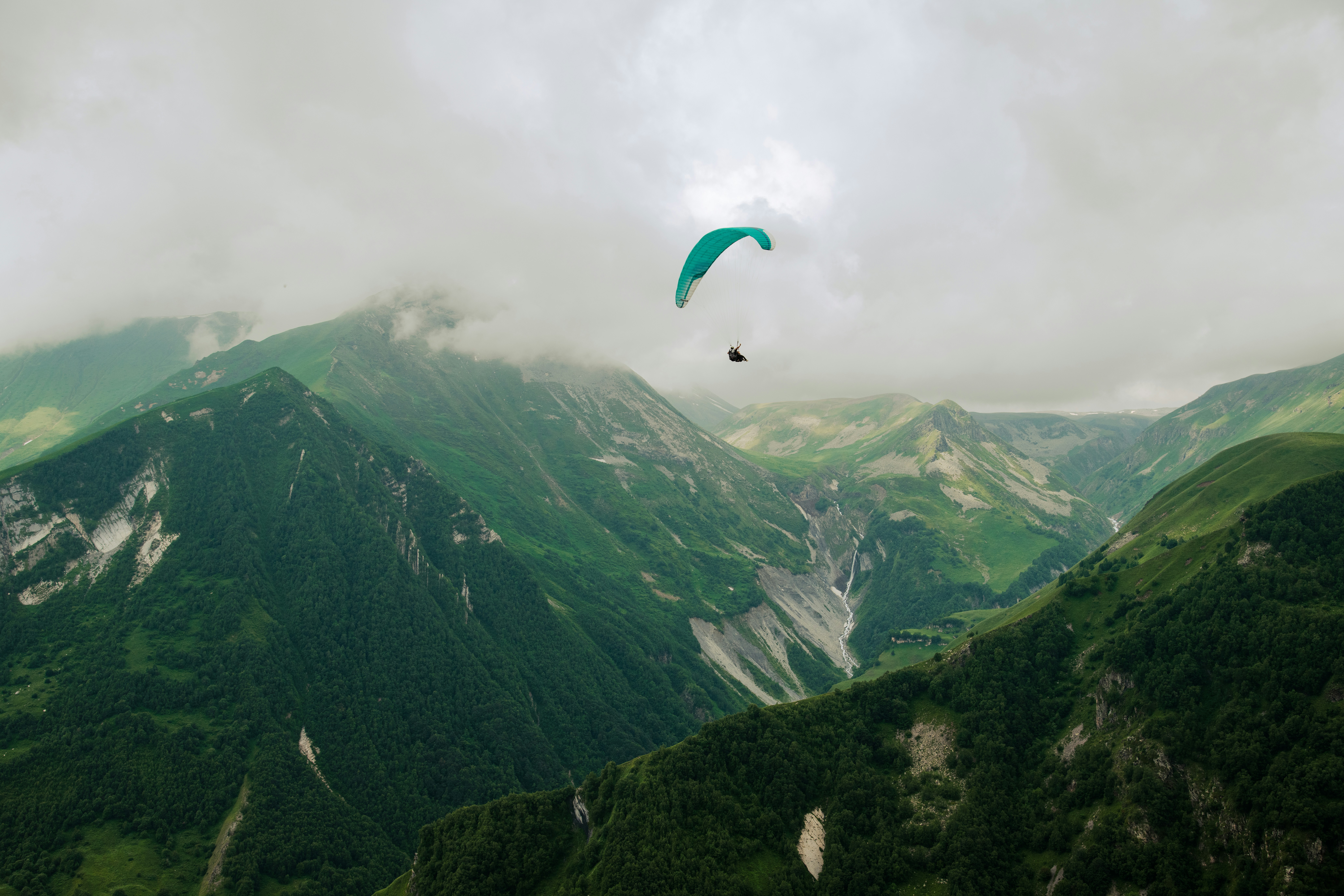 Green Ridge Sky: A Paraglider Traverses a Serene Alpine Gorge