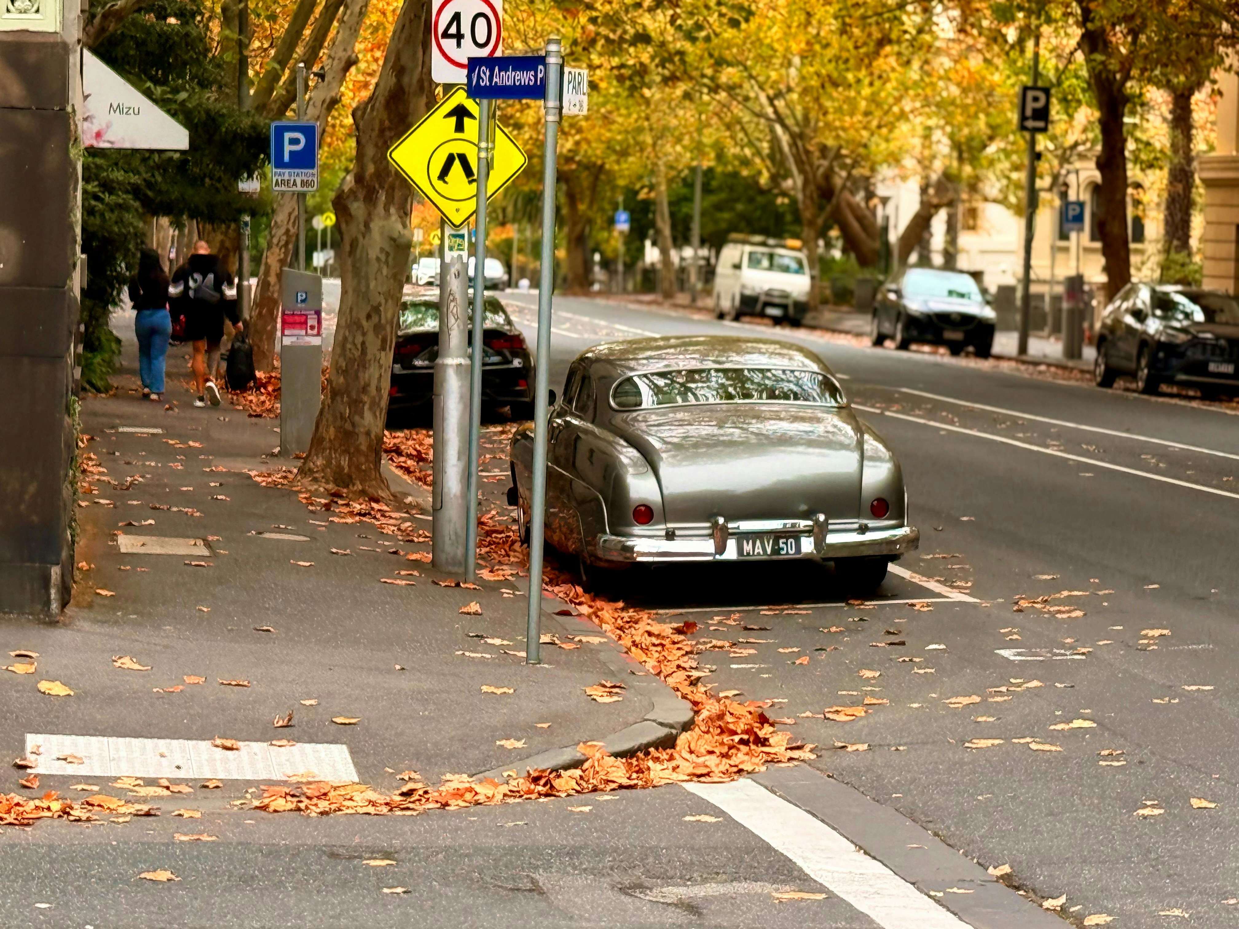 Autumn Streetcar: A Vintage Car Resting Amid Fallen Leaves