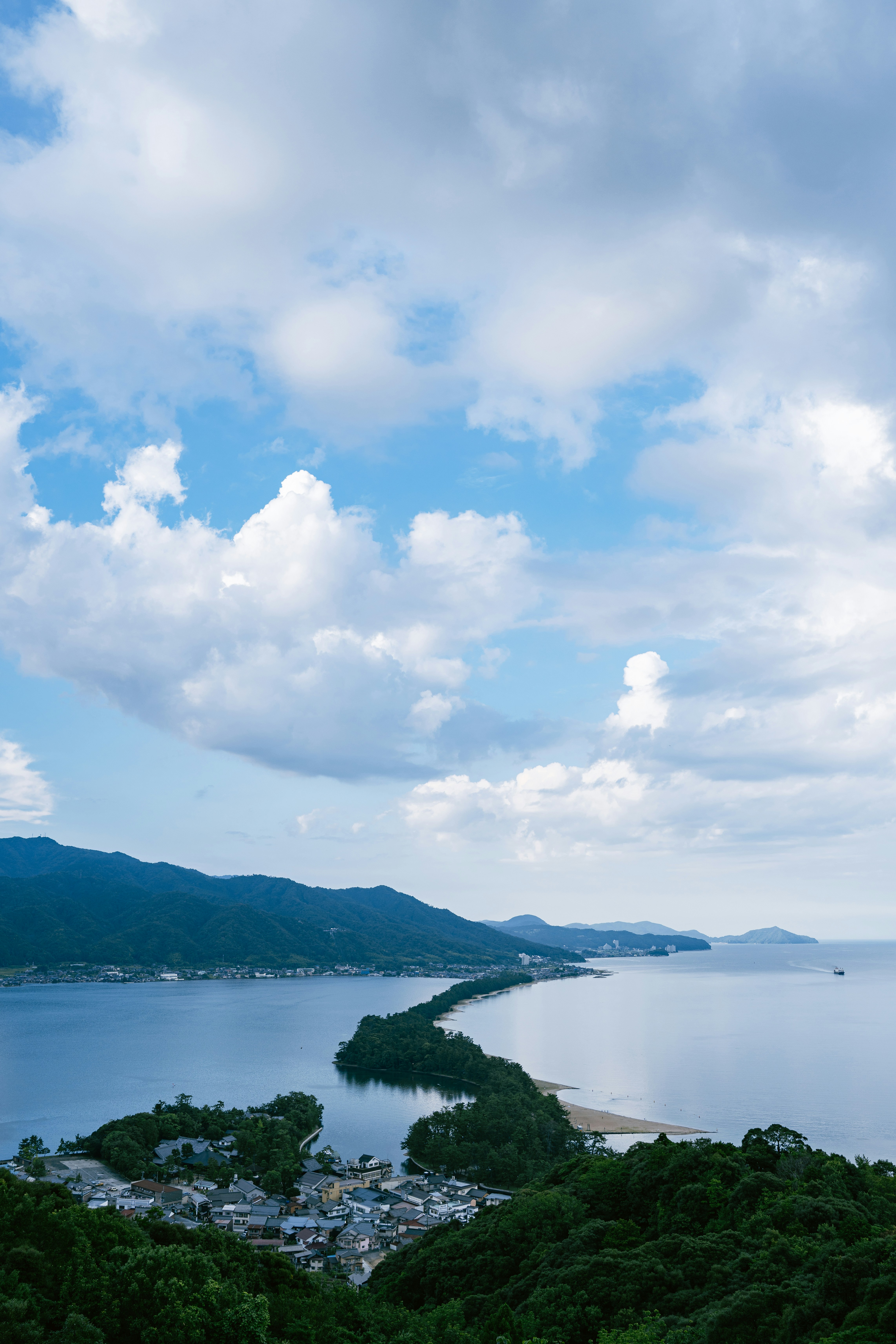 Coastal Peninsula Drifts into the Sea Under Puffy Summer Clouds