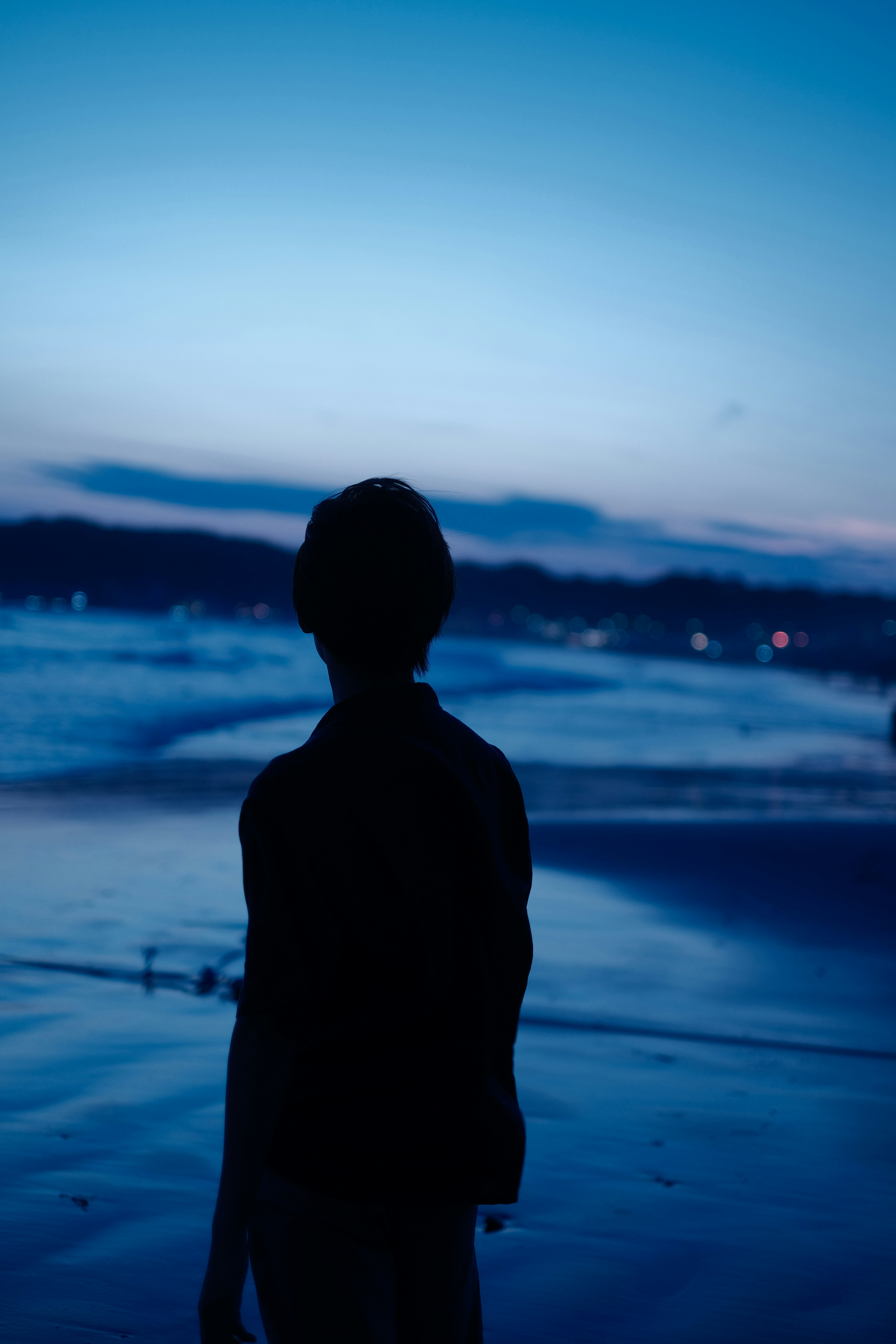 Midnight Shoreline: A Silhouette Against Quiet Ocean Blues