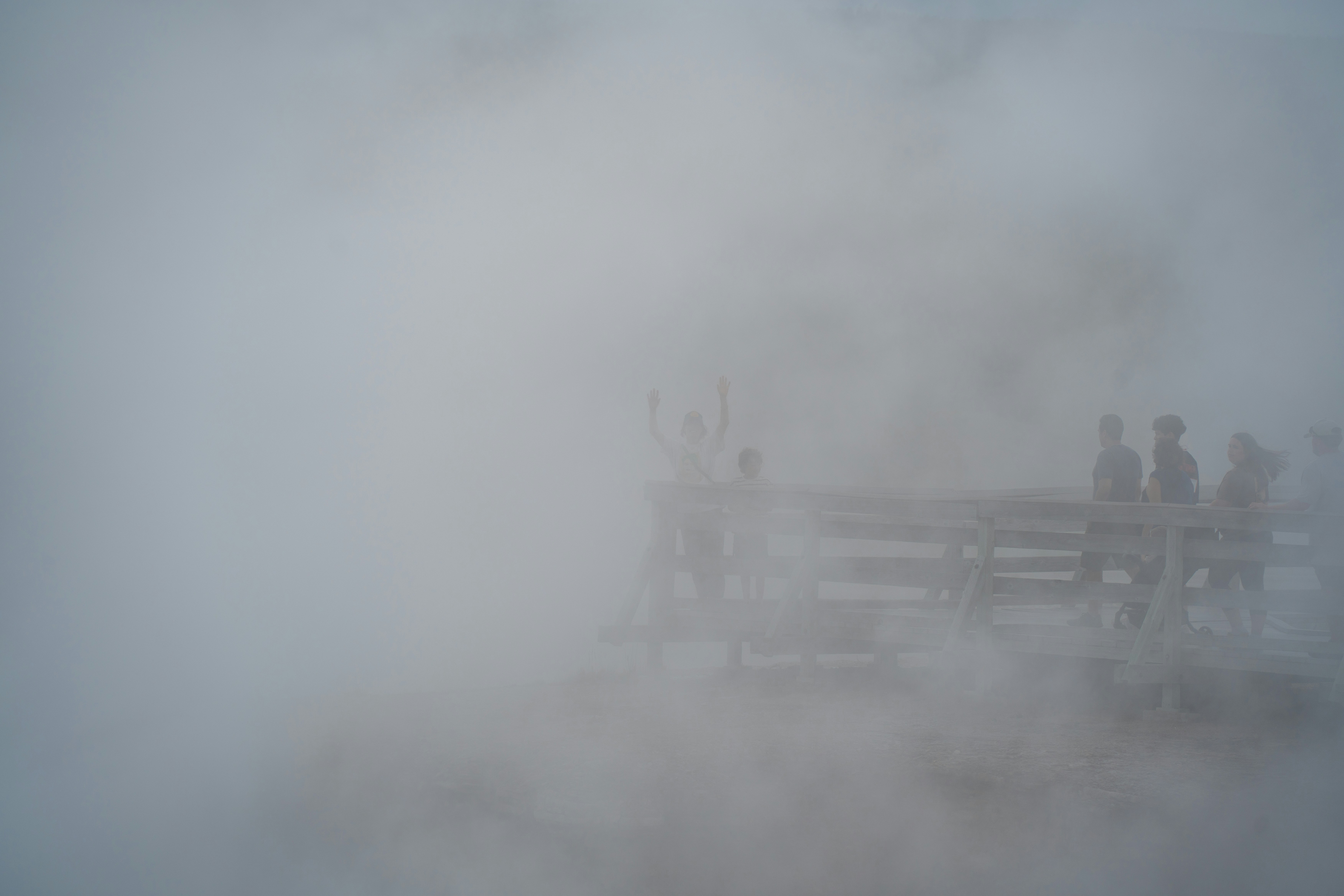 Quiet Frontier: People Hushed by Steam on a Wooden Walkway