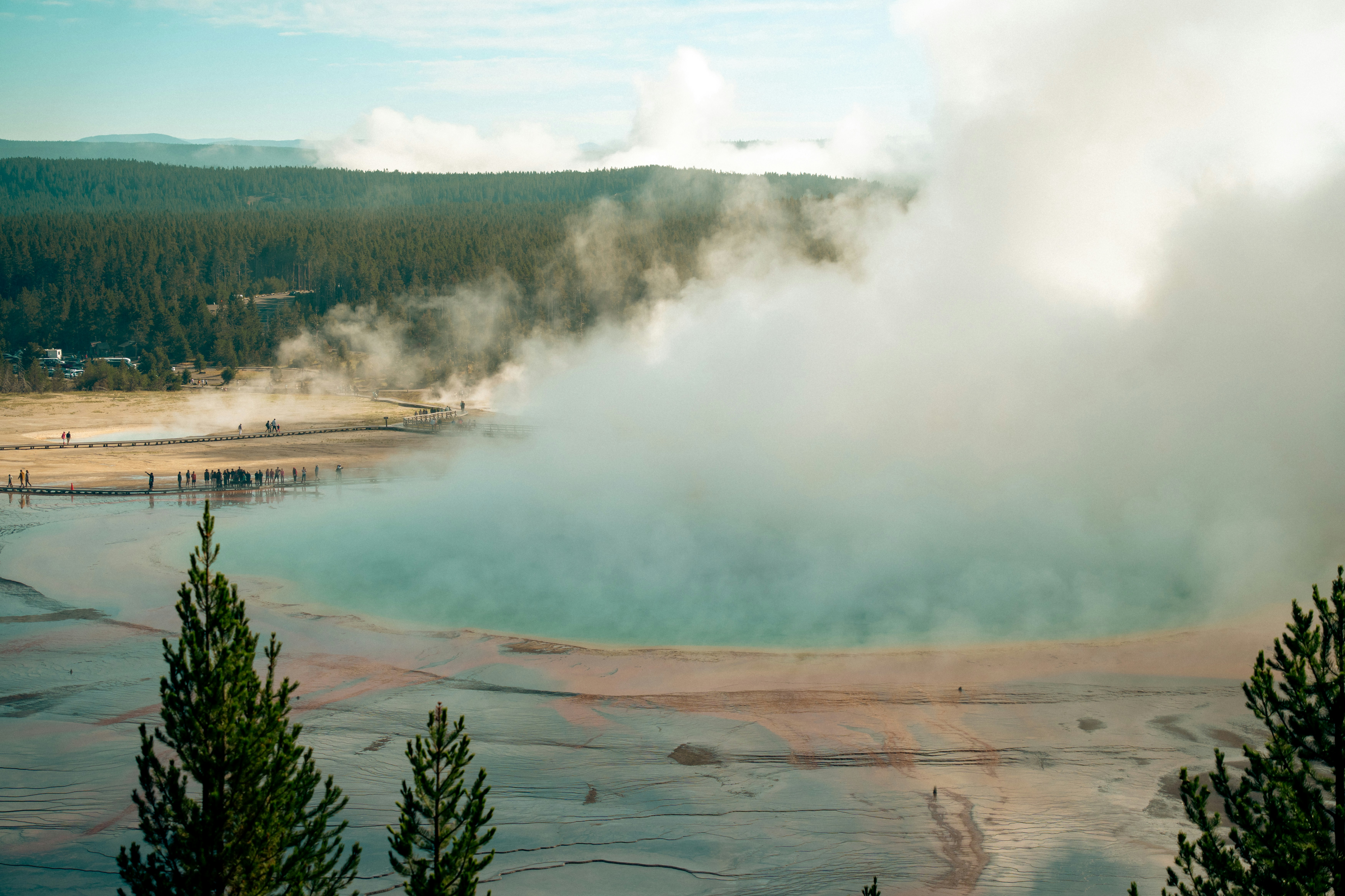 Steaming Emerald Basin Beyond a Forest Rim