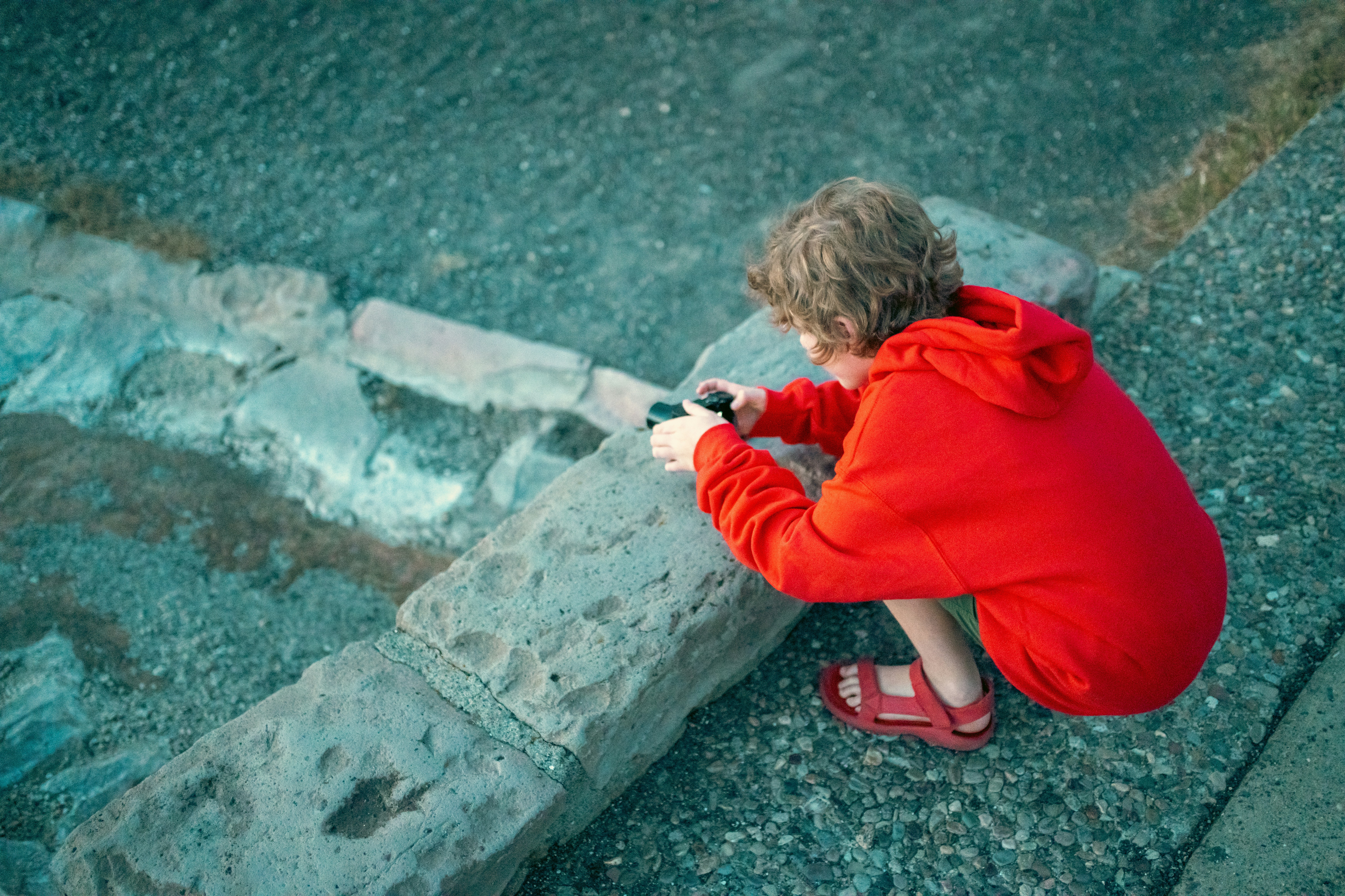 Red Hoodie, Quiet Focus: A Young Photographer on the Edge of the Stone Border