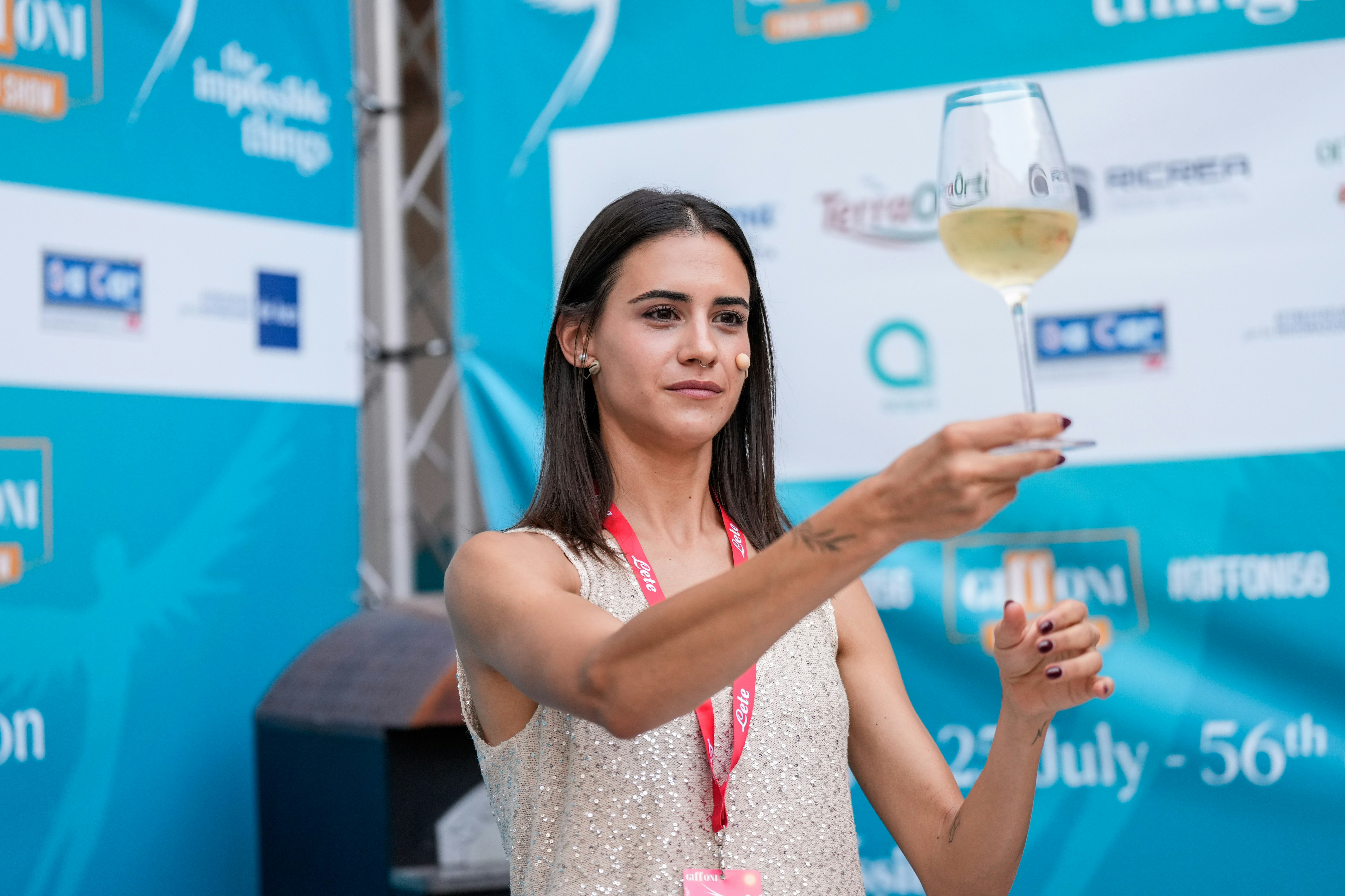 Toast of the Stage: A confident presenter raises a glass at a blue-carpet event
