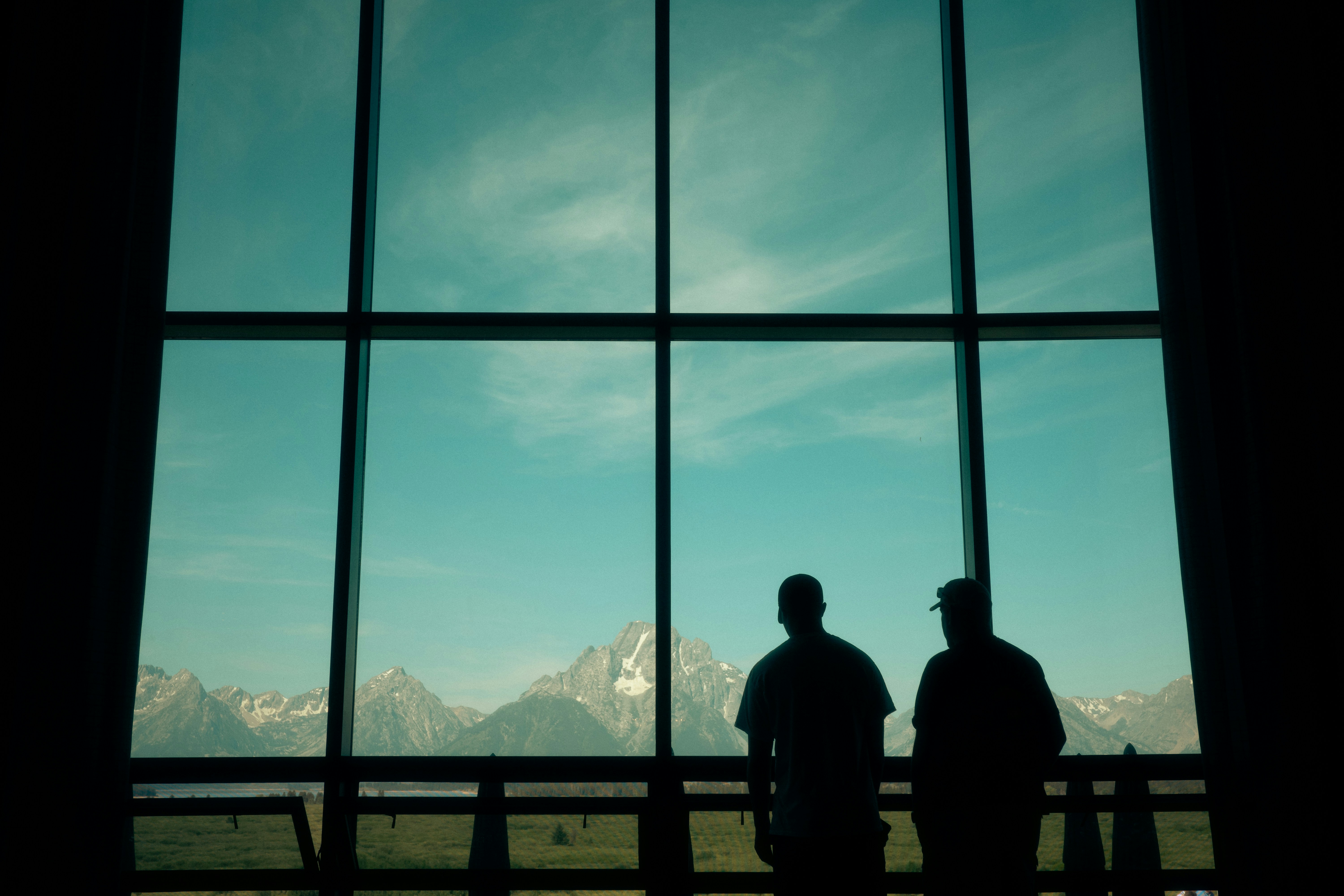 Windowed Horizons: Two Silhouettes Against Alpine Light