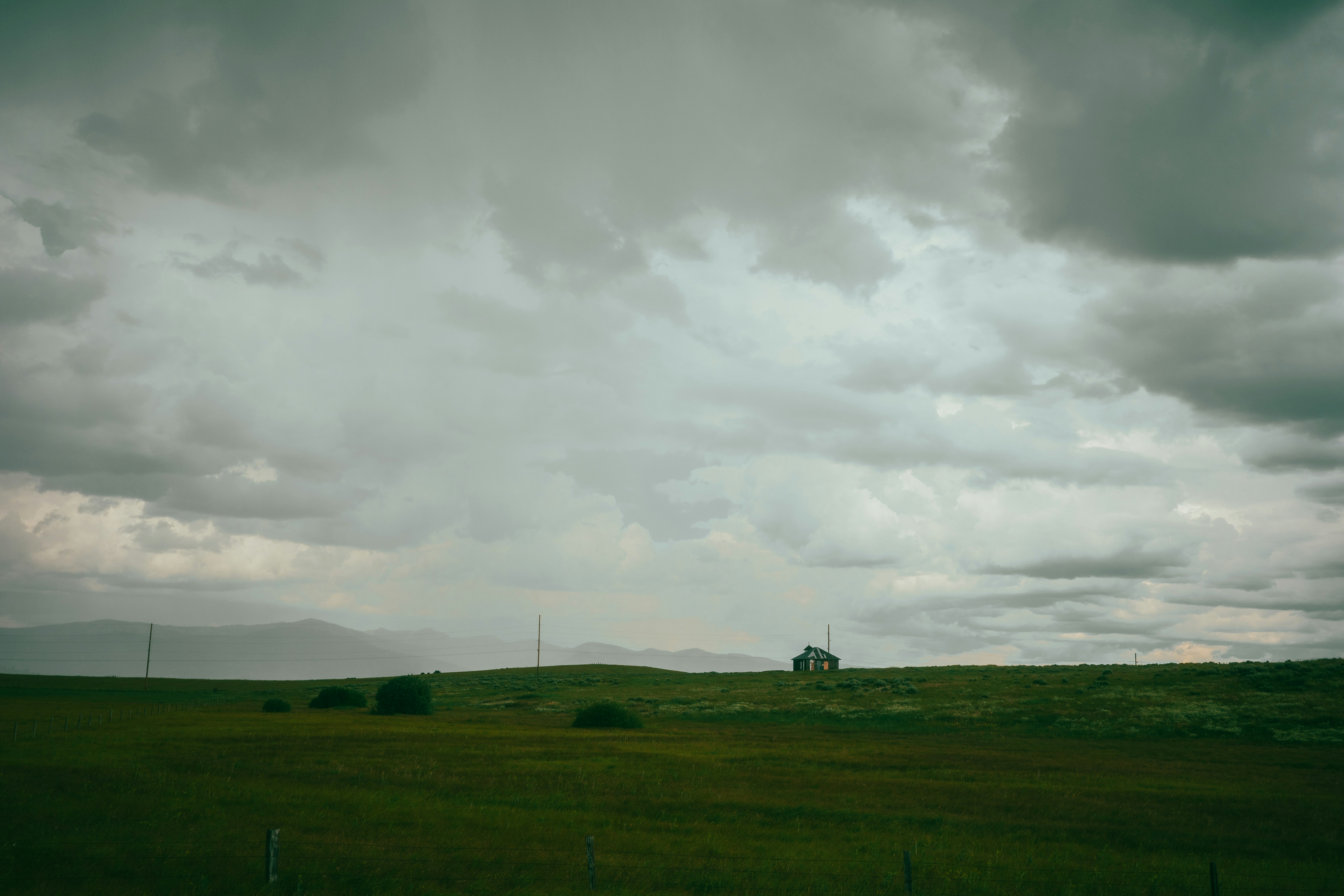 Horizon Break: A lone structure on the grassland under a moody sky