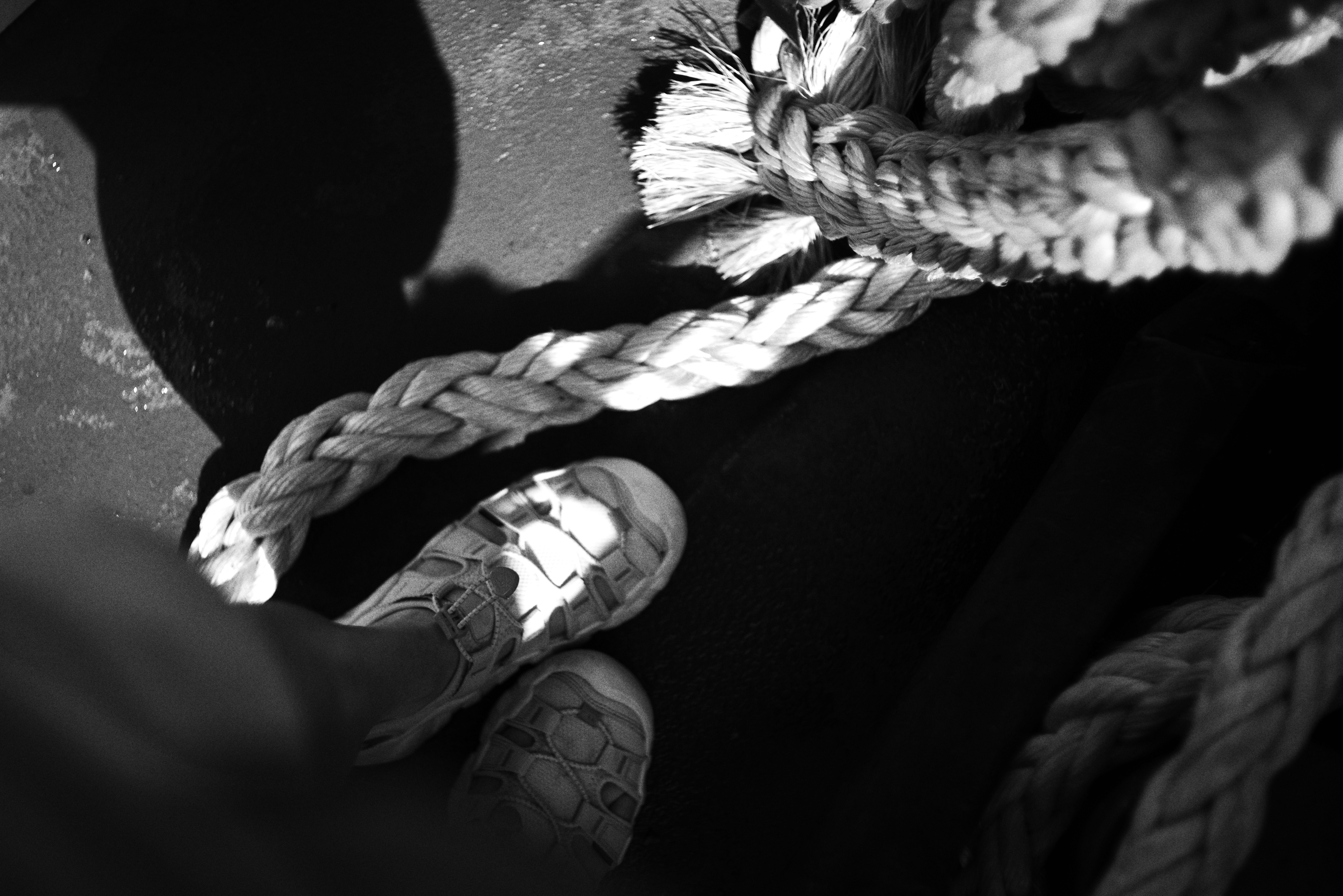 Booted steps on a coiled rope: a grayscale moment on deck