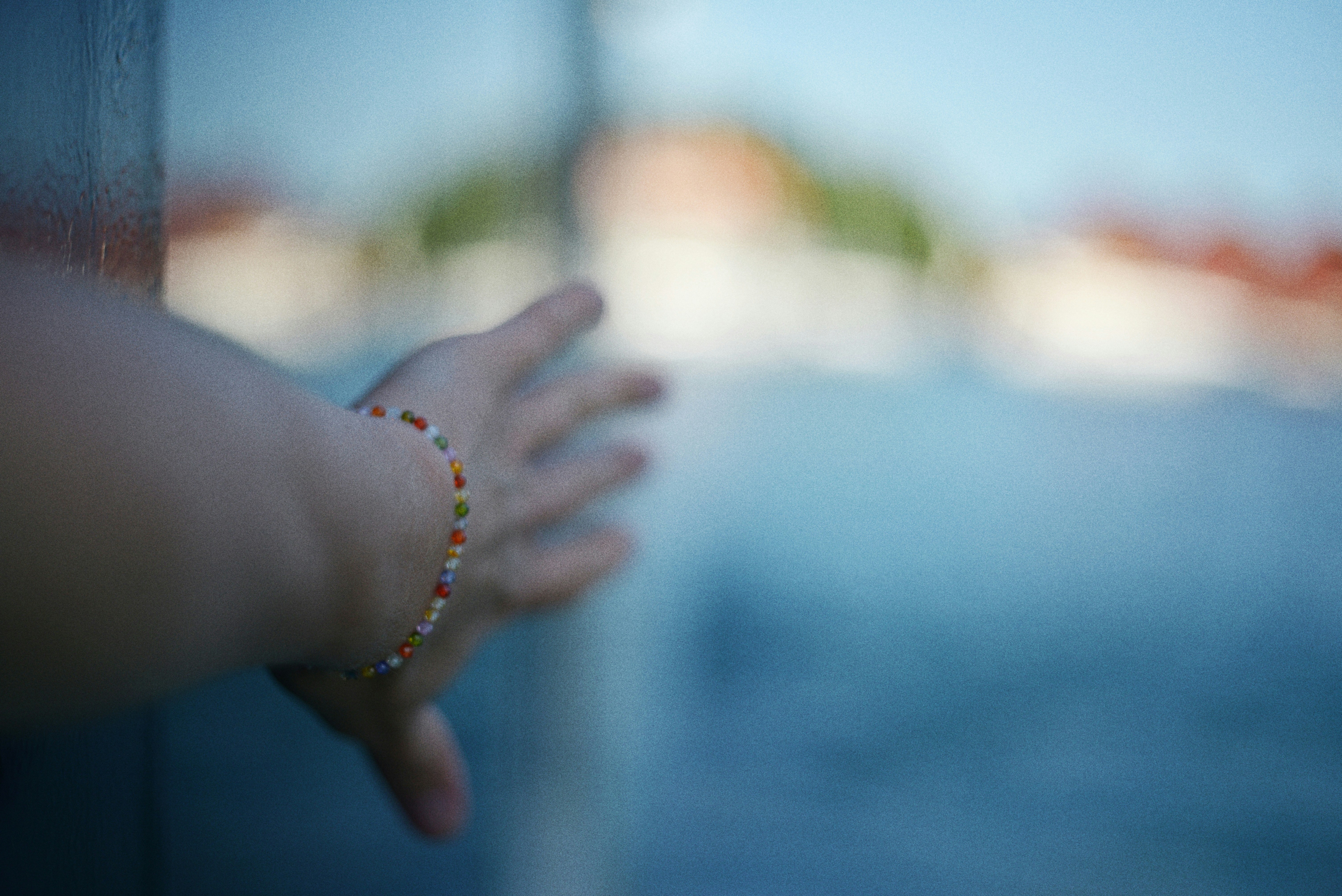 Outstretched Hand Through Glass: A Tiny World of Colorful Beads
