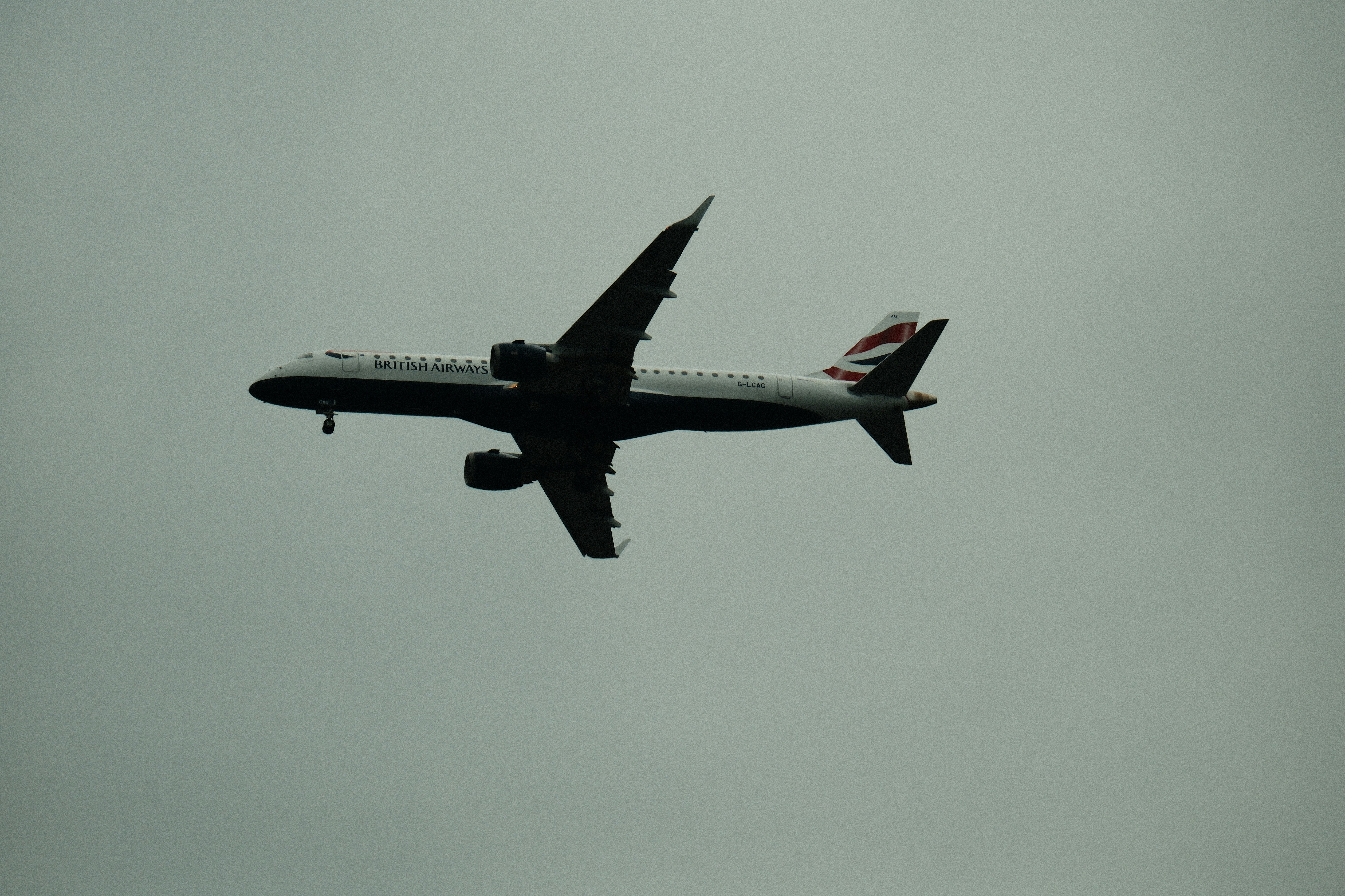 Midflight silhouette: a distant airliner gliding through gray skies