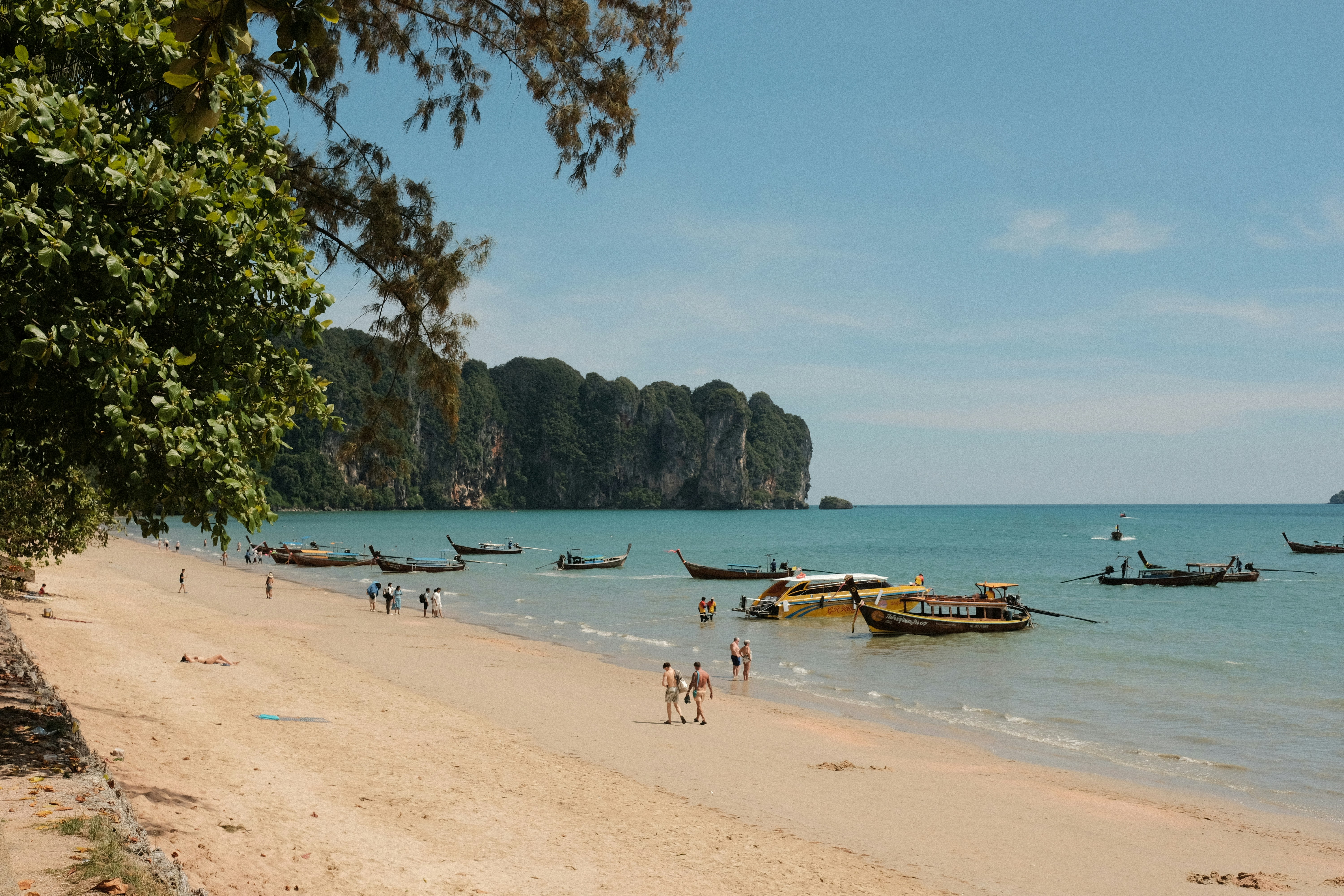 Sunlit Strand with Distant limestone cliffs and Fishing Boats