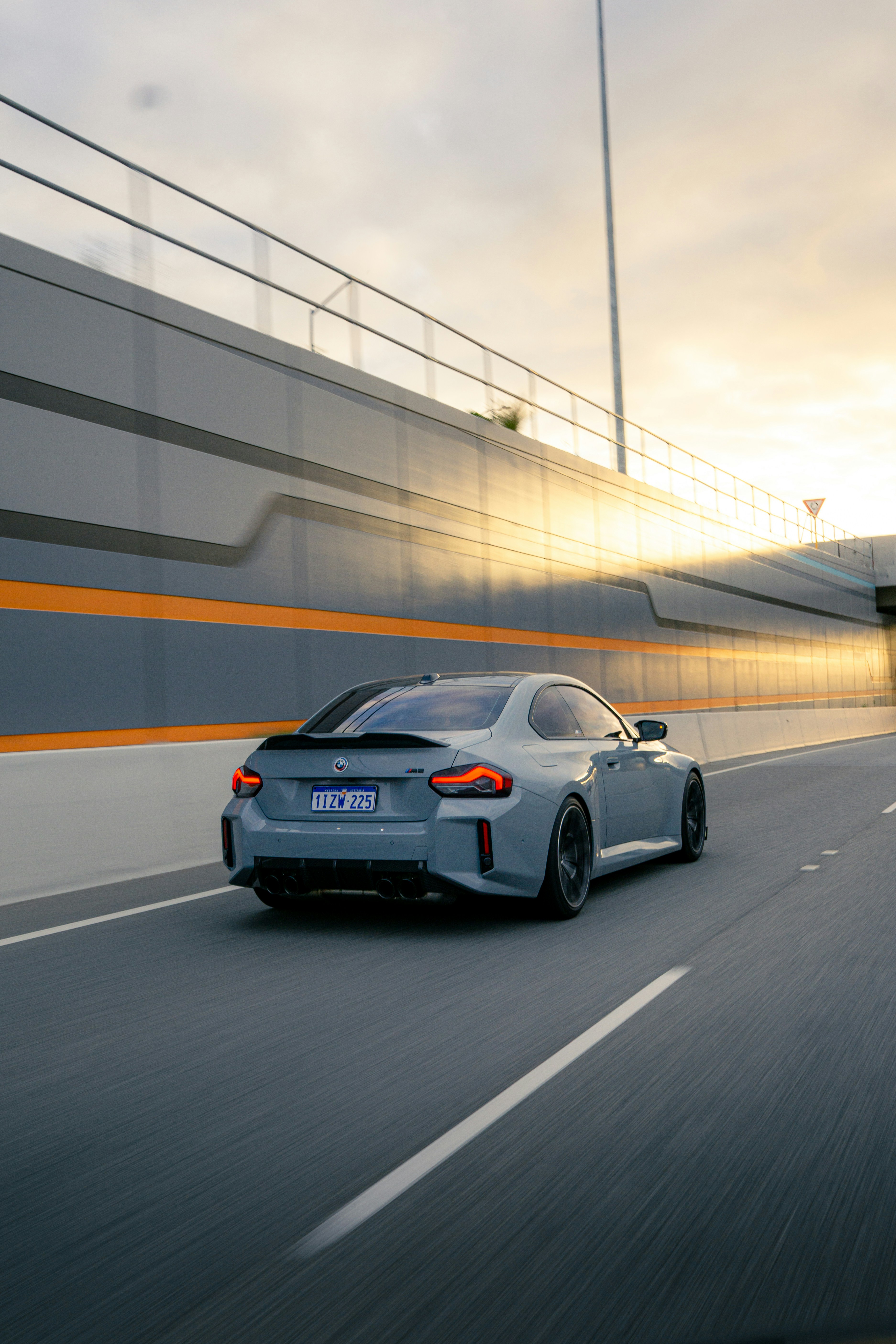 Blue sports coupe streams through a sunlit urban tunnel