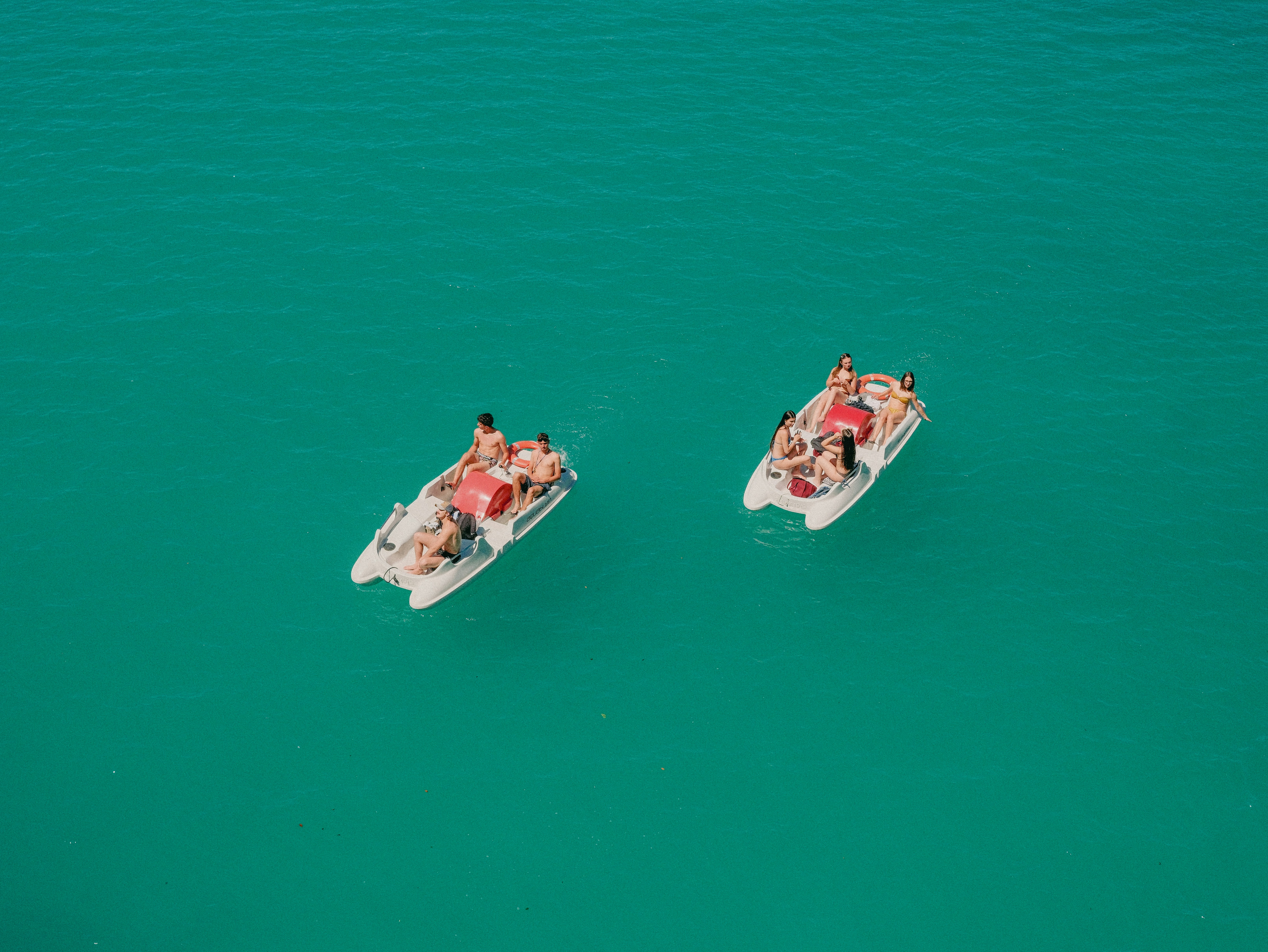 Two Red-Trimmed Speedboats Cut Across Turquoise Sea