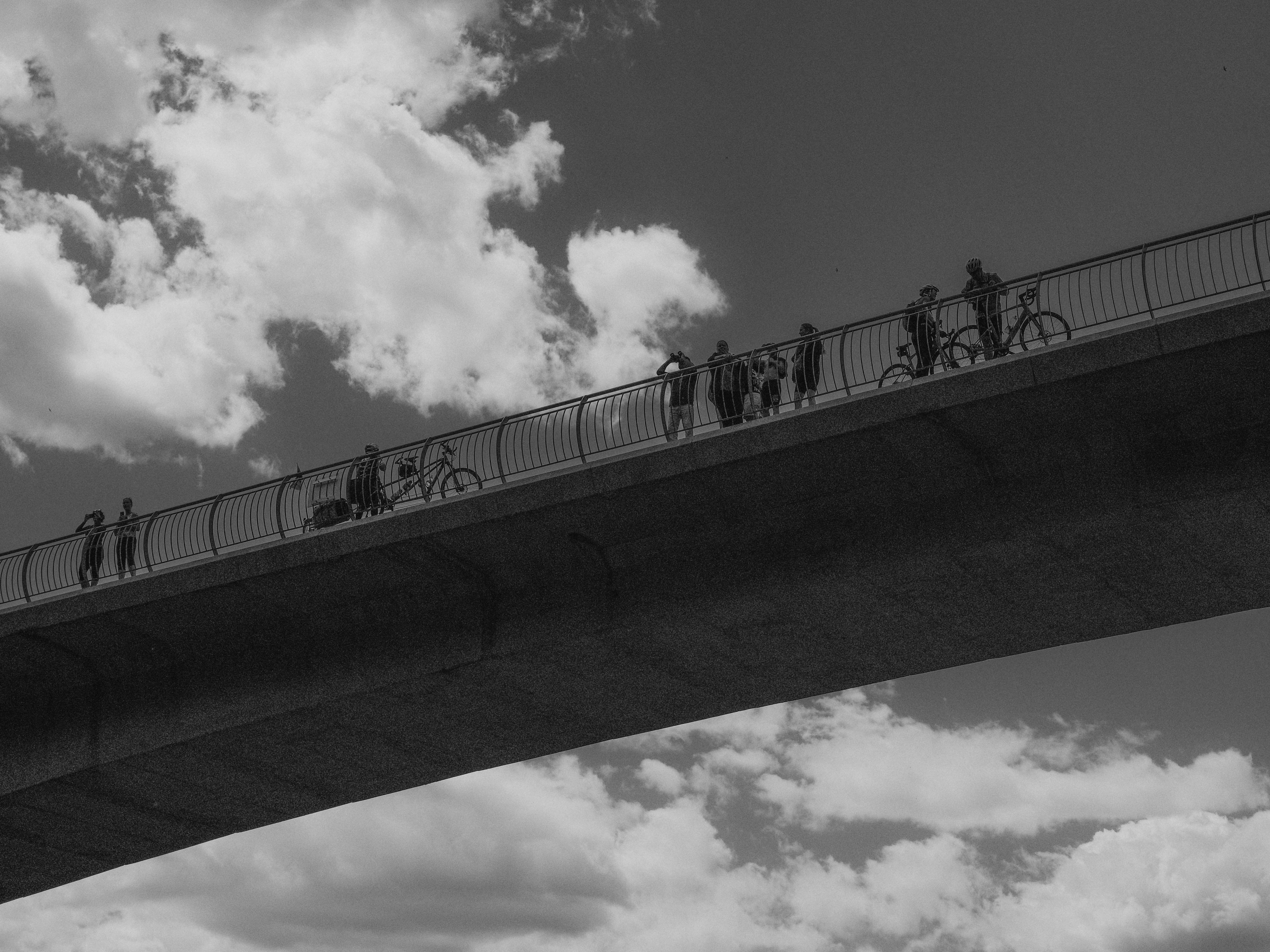 Pedestrian Parade over Steel Arc: Bicycles and Walkers on a Sundown Bridge