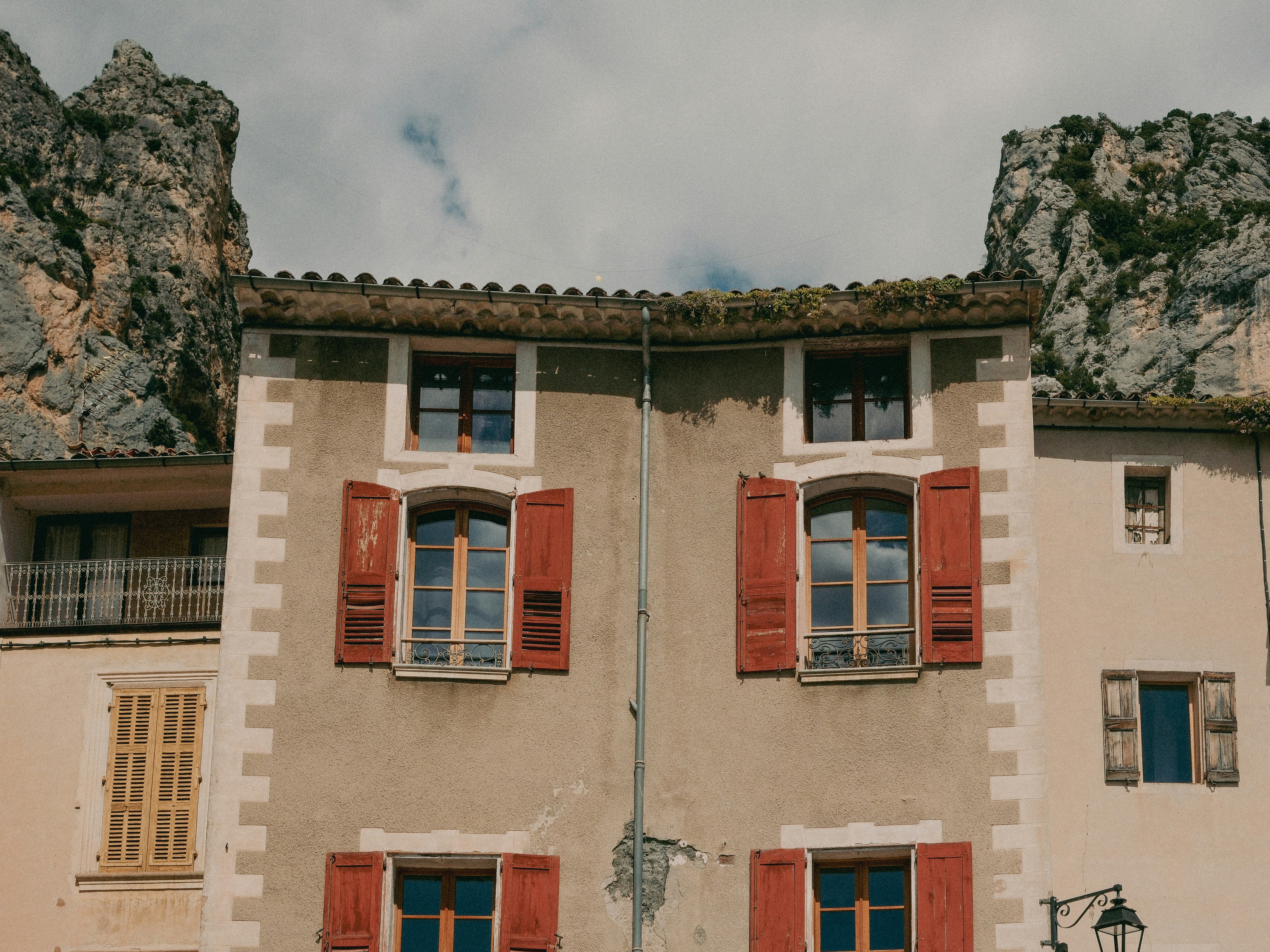 Adobe Stucco Facade with Red Shutters Amid Craggy Cliffscape