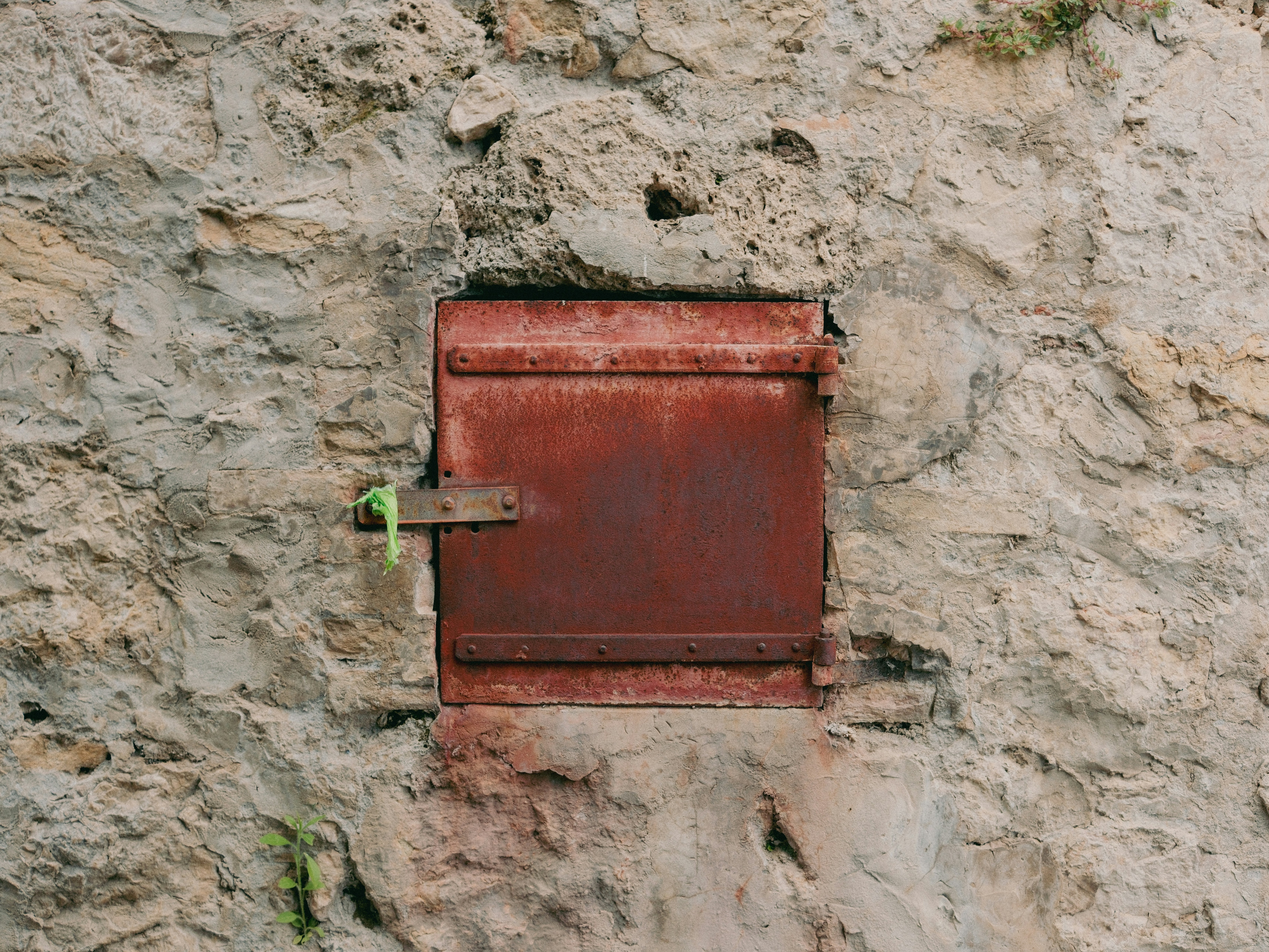 Rusty Red Hatch in Weathered Stone Wall