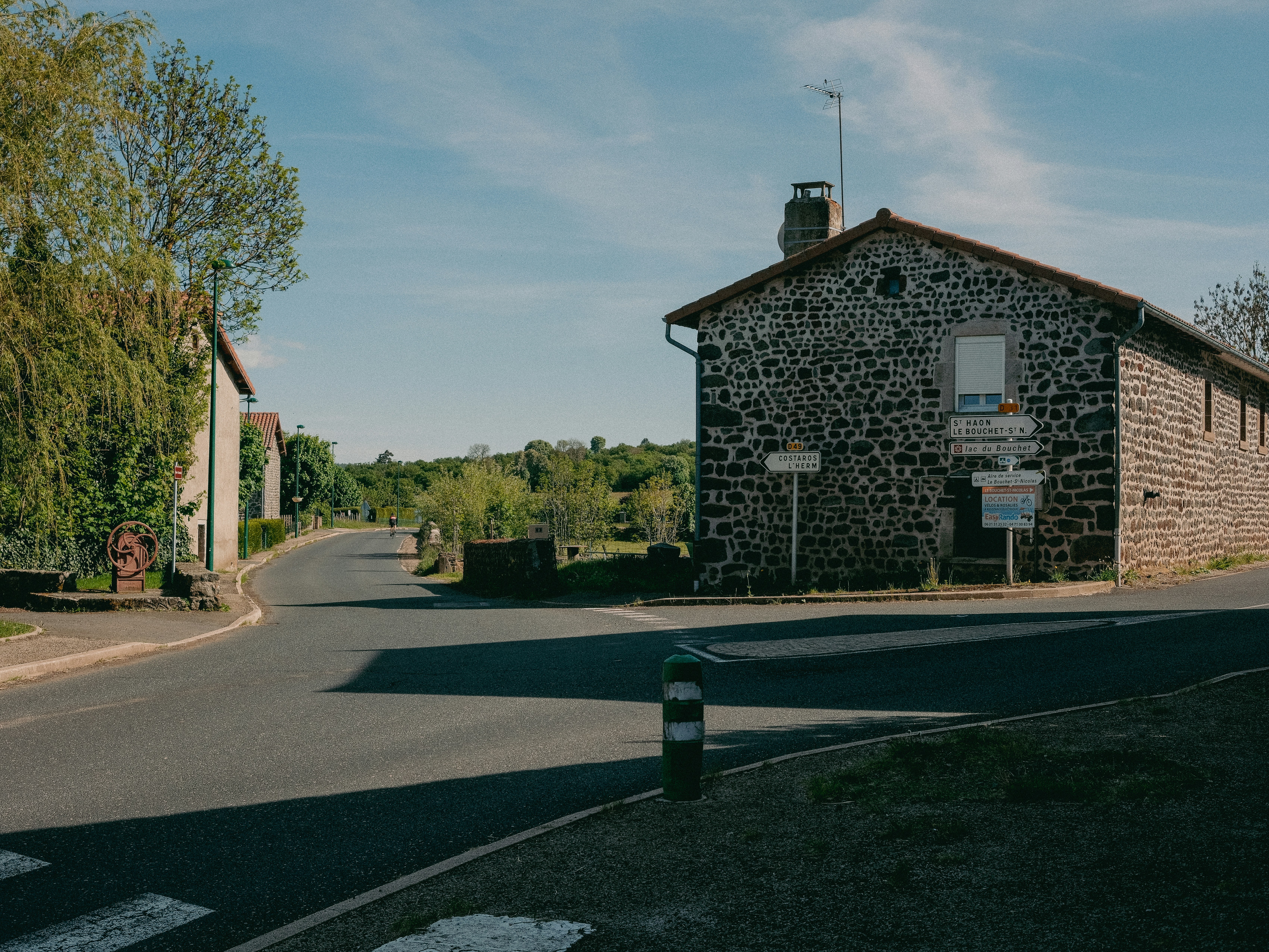 Stone Cottage at the Corner: Quiet Village Street Under Blue Sky