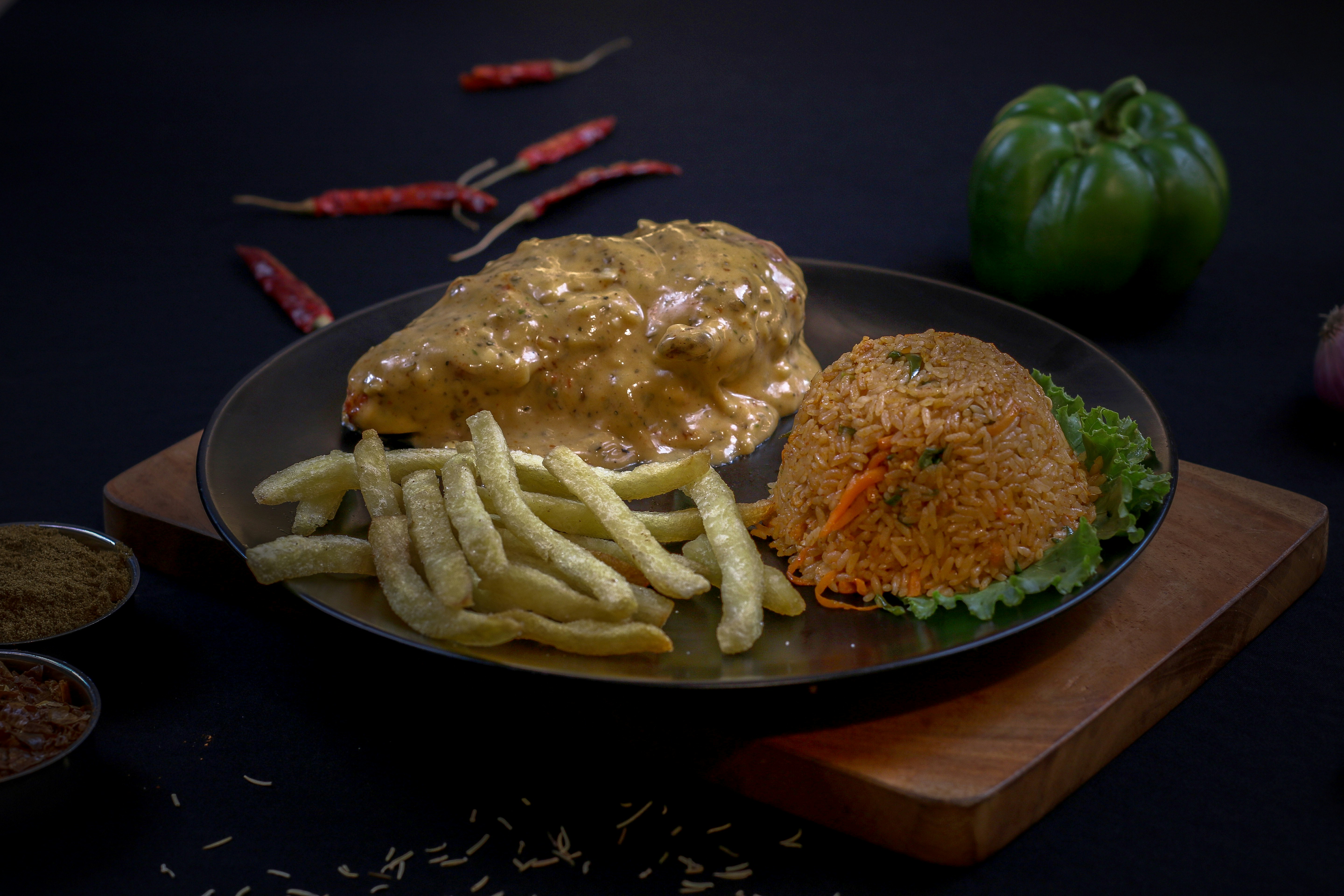 Saucy Chicken and Fries with Pyramid Rice on a Dark Platter