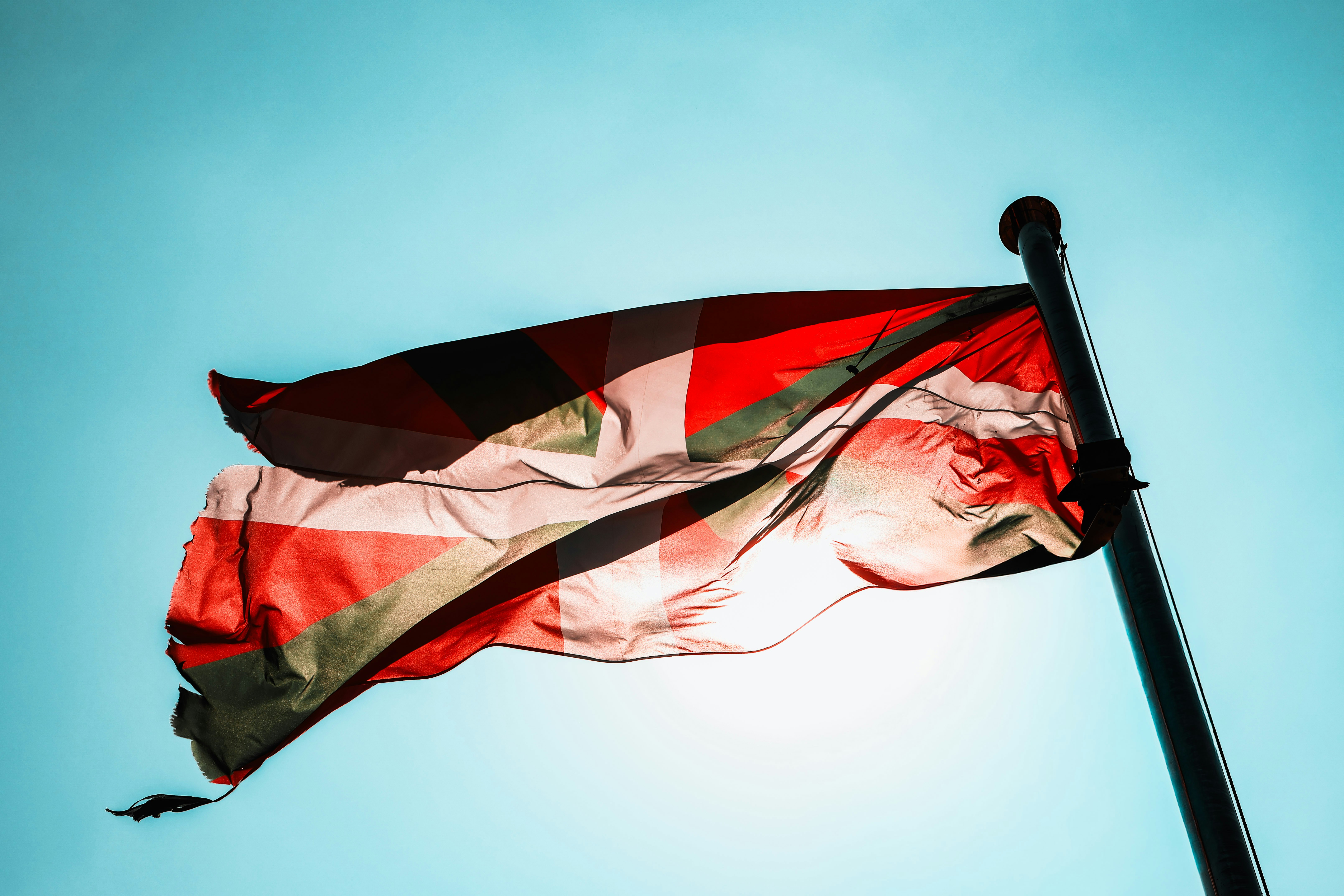 Flag on the Wind: A Flagpole Backlit by the Sun in a Clear Sky