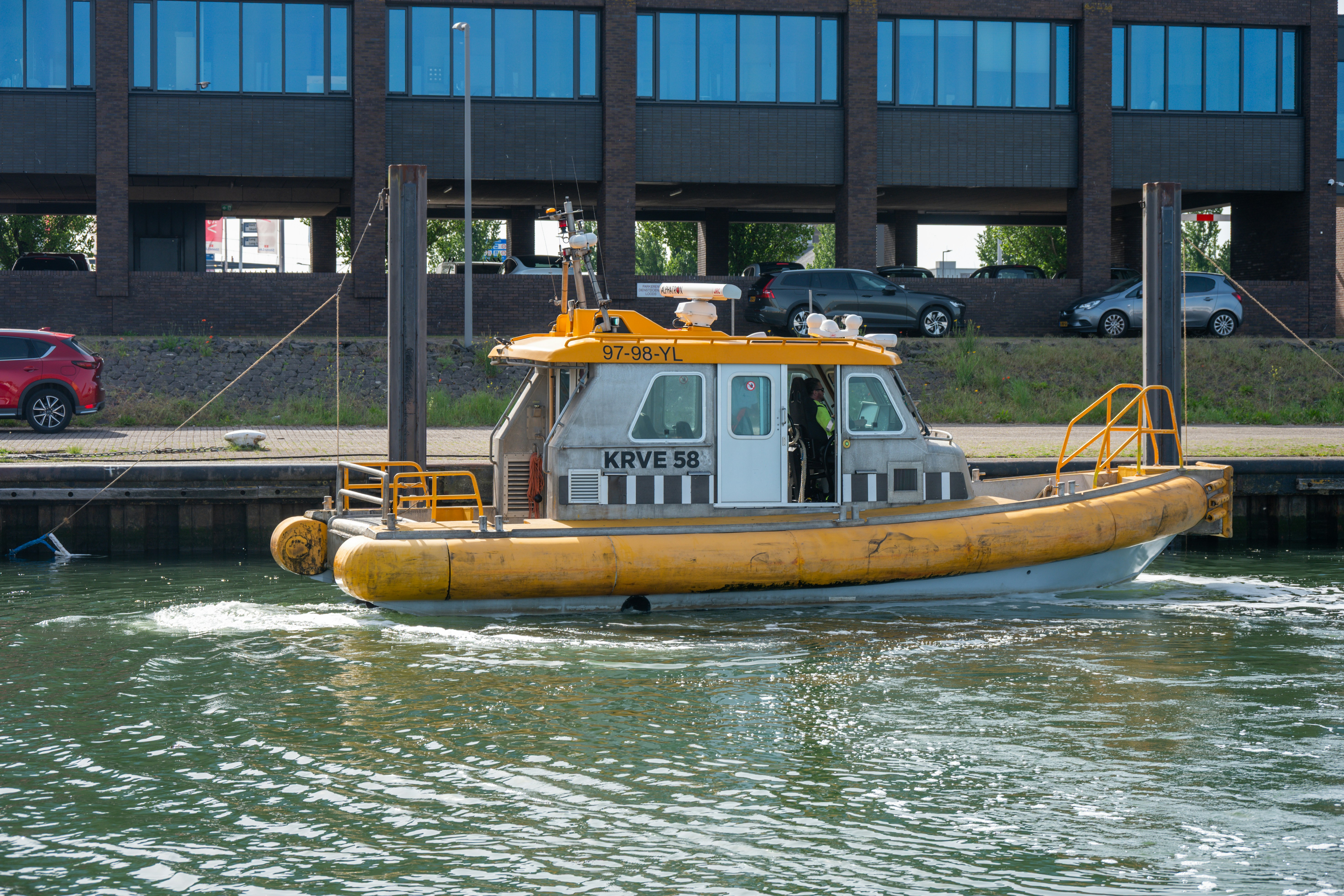 Yellow Utility Boat Drifting Along a Quiet Waterfront